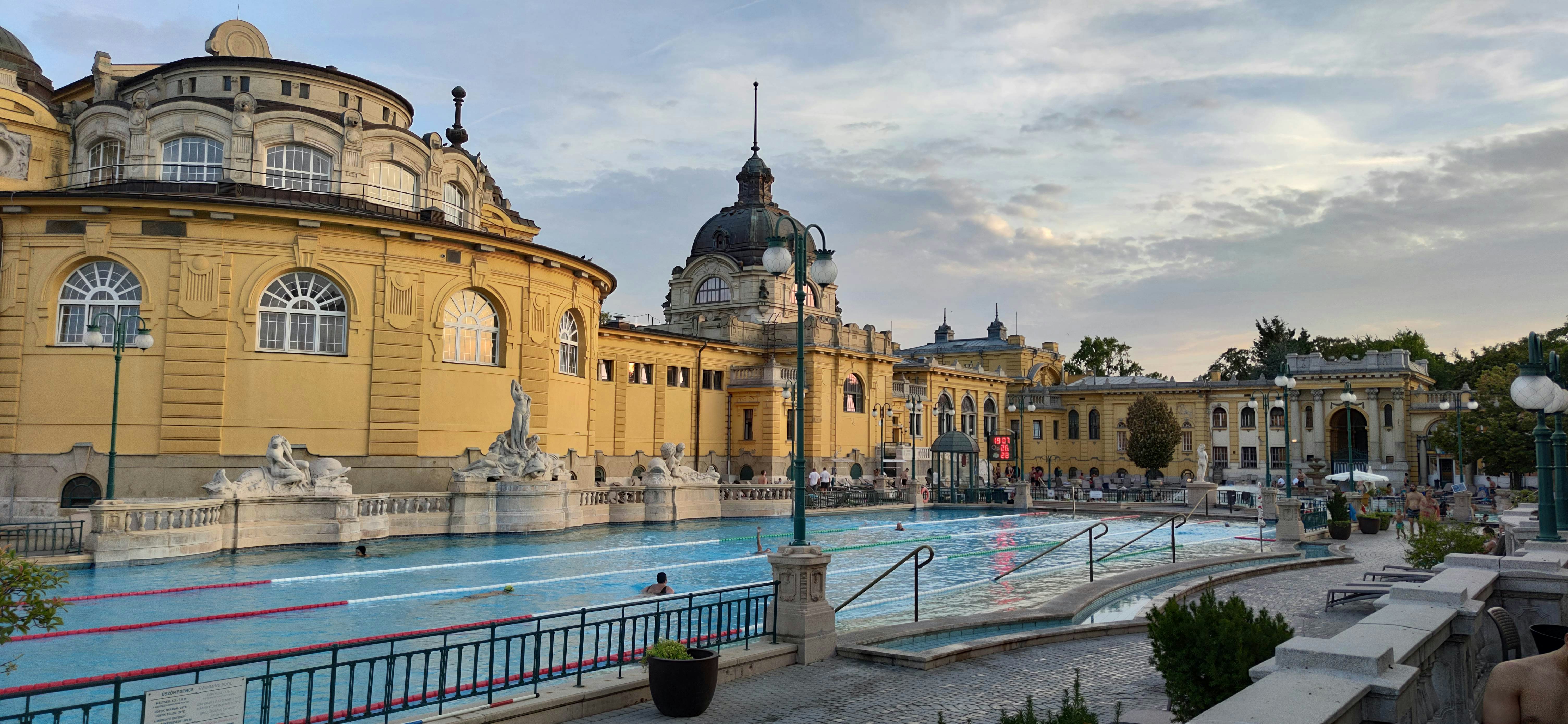 Historic spa complex featuring a large swimming pool with ornate architecture and gentle evening light.