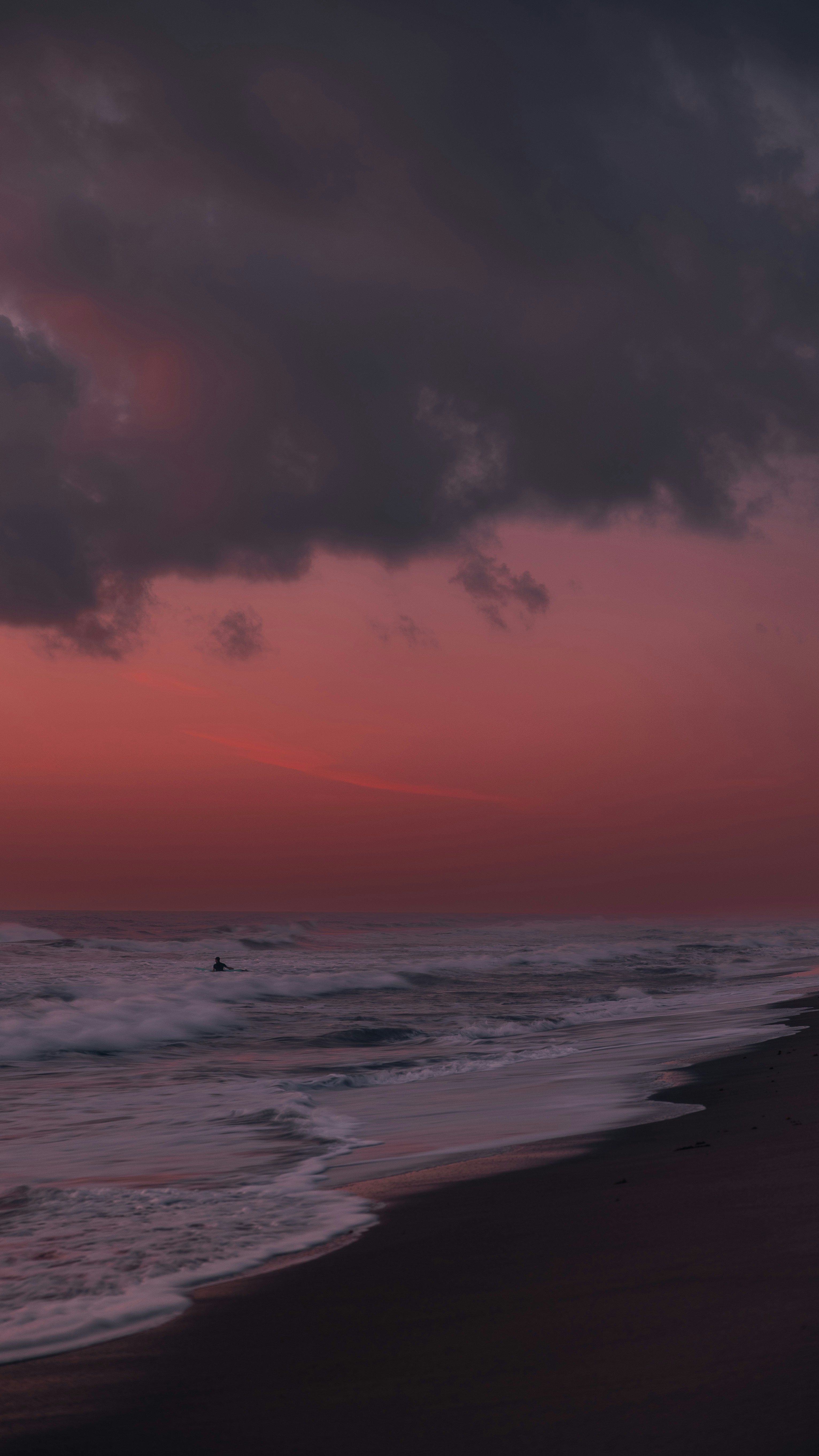 Crimson Tide at Dusk: A Quiet Shore Under Dark Clouds