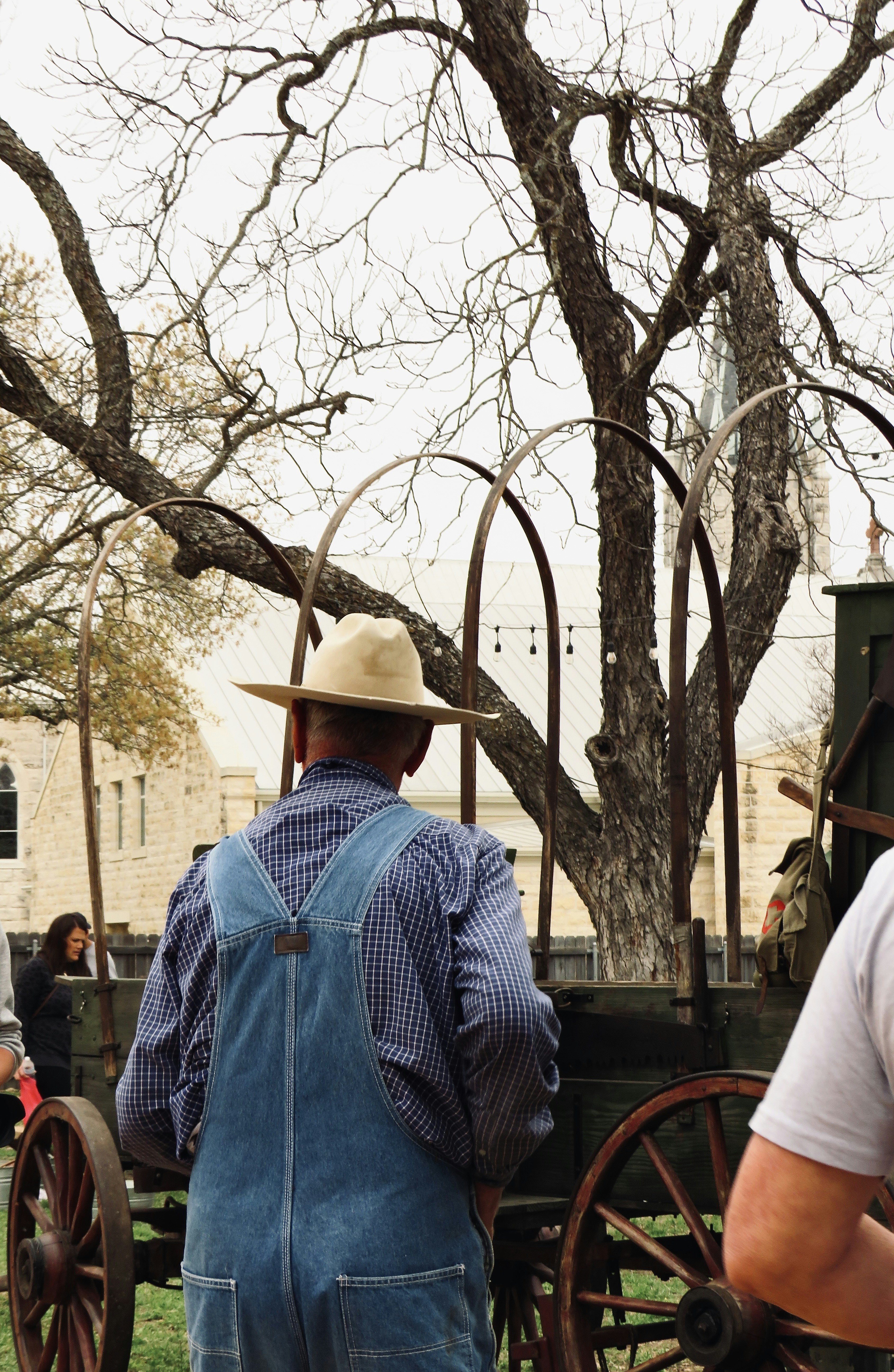 A man in overalls and a cowboy hat standing next to a wagon photo ...