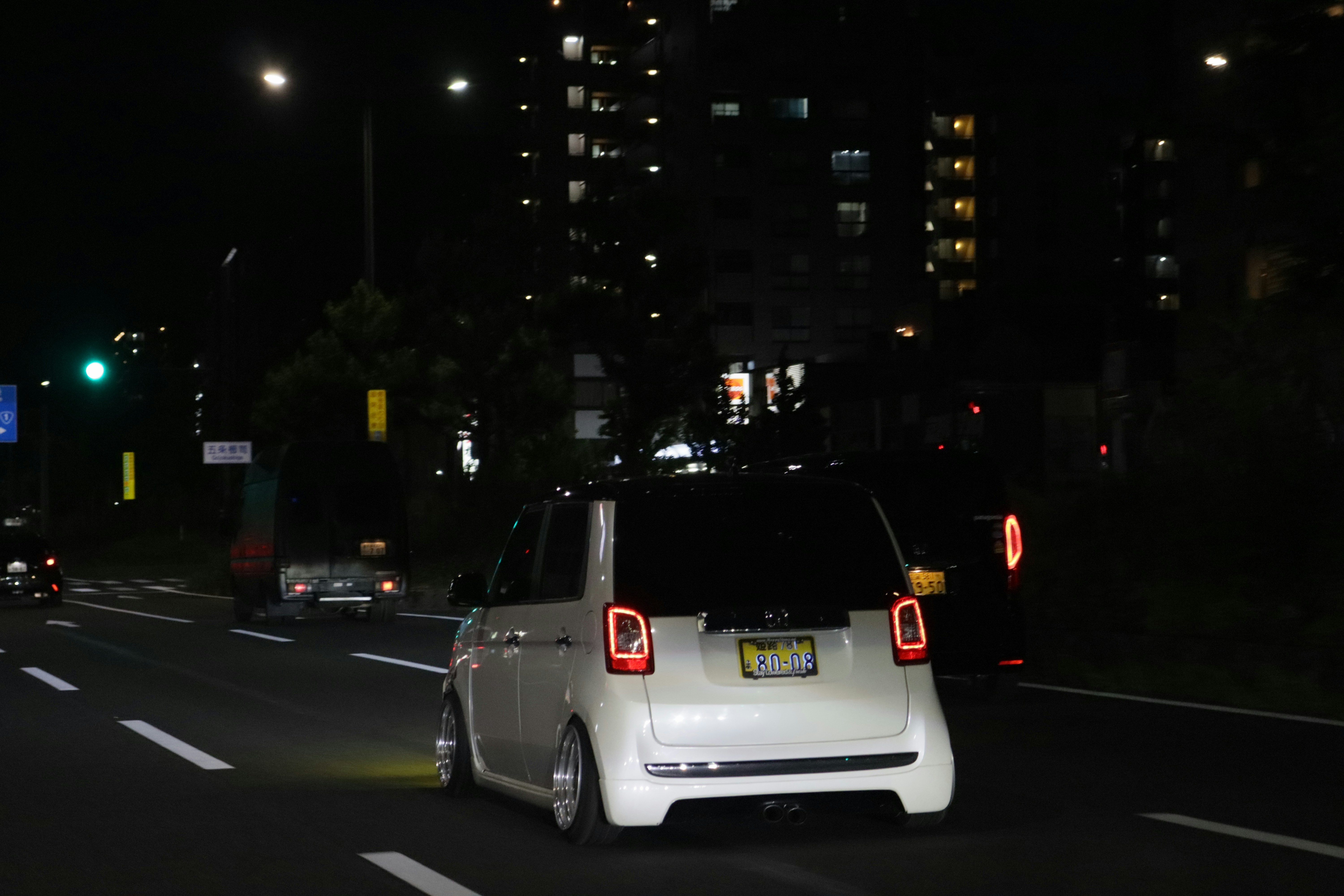 Rear Glint in the Night: A White Hatchback on a Quiet City Street