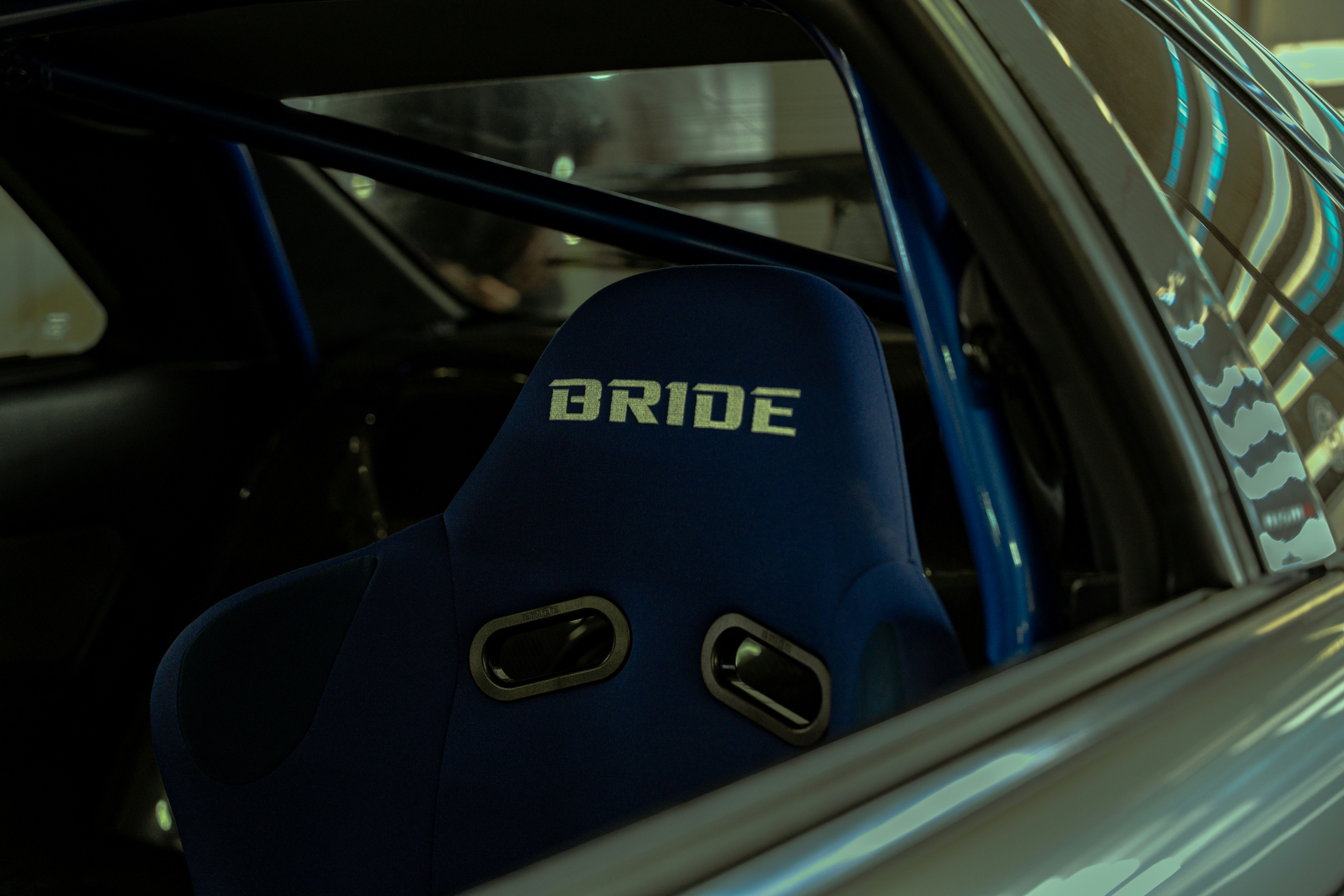 Blue racing seat with 'BRIDE' branding inside a car's interior.