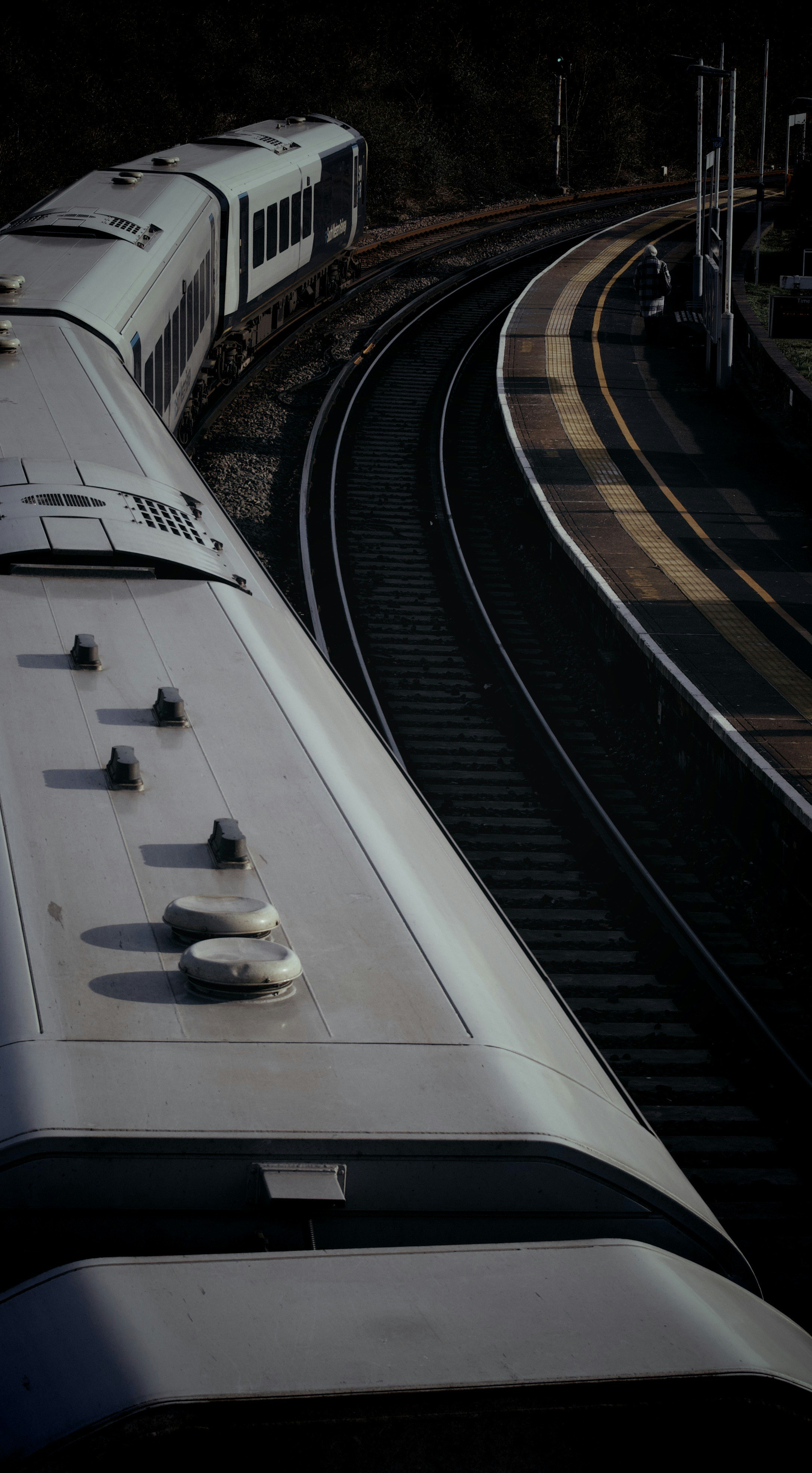 Overhead Arc: White Train Tracing a Crescent Through Evening Rails