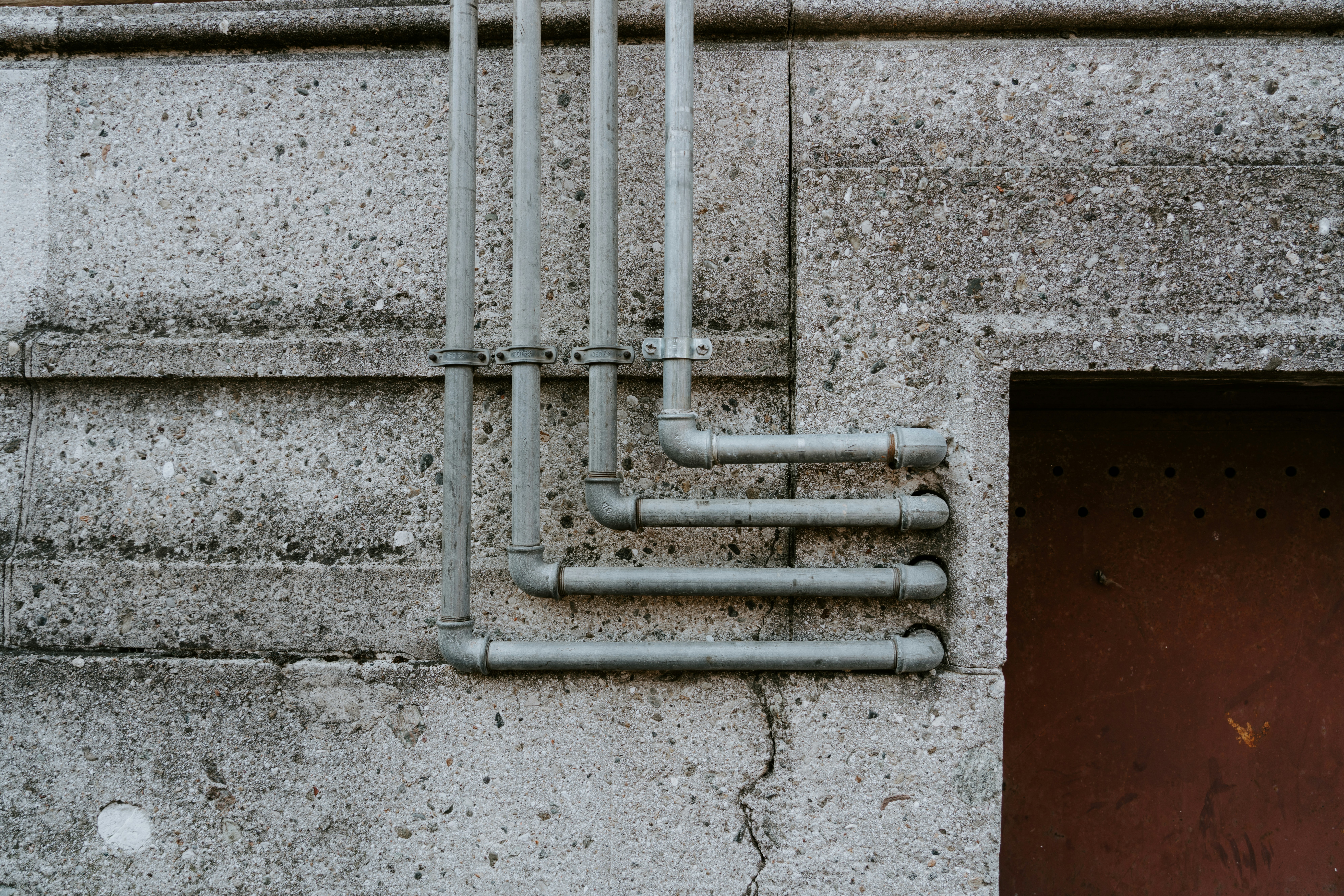 A wall with a bunch of pipes attached to it photo – Free Pipes Image on ...