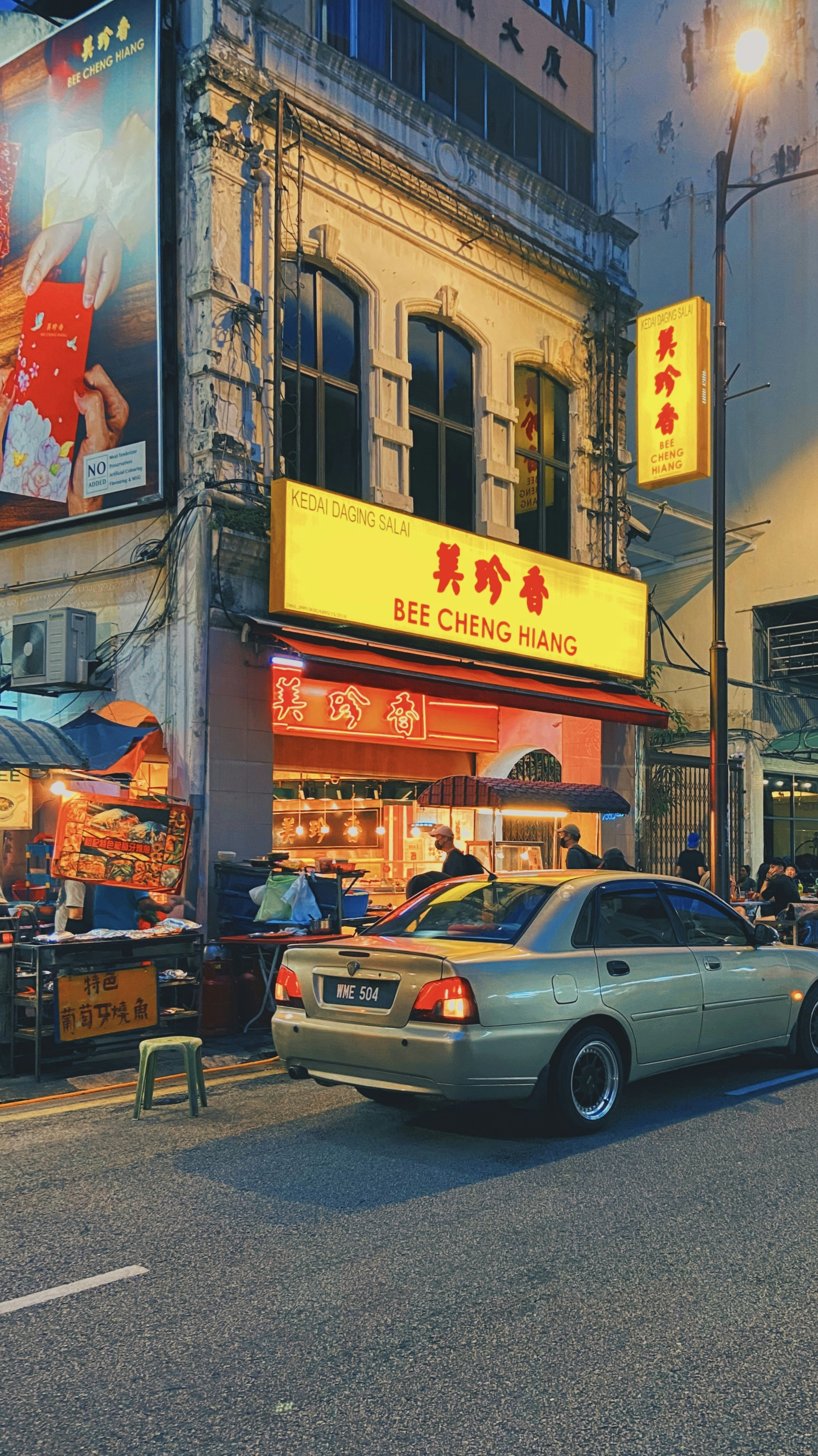 Bee Cheng Hiang at Dusk: Neon Signs, Market Stalls, and a Silver Sedan