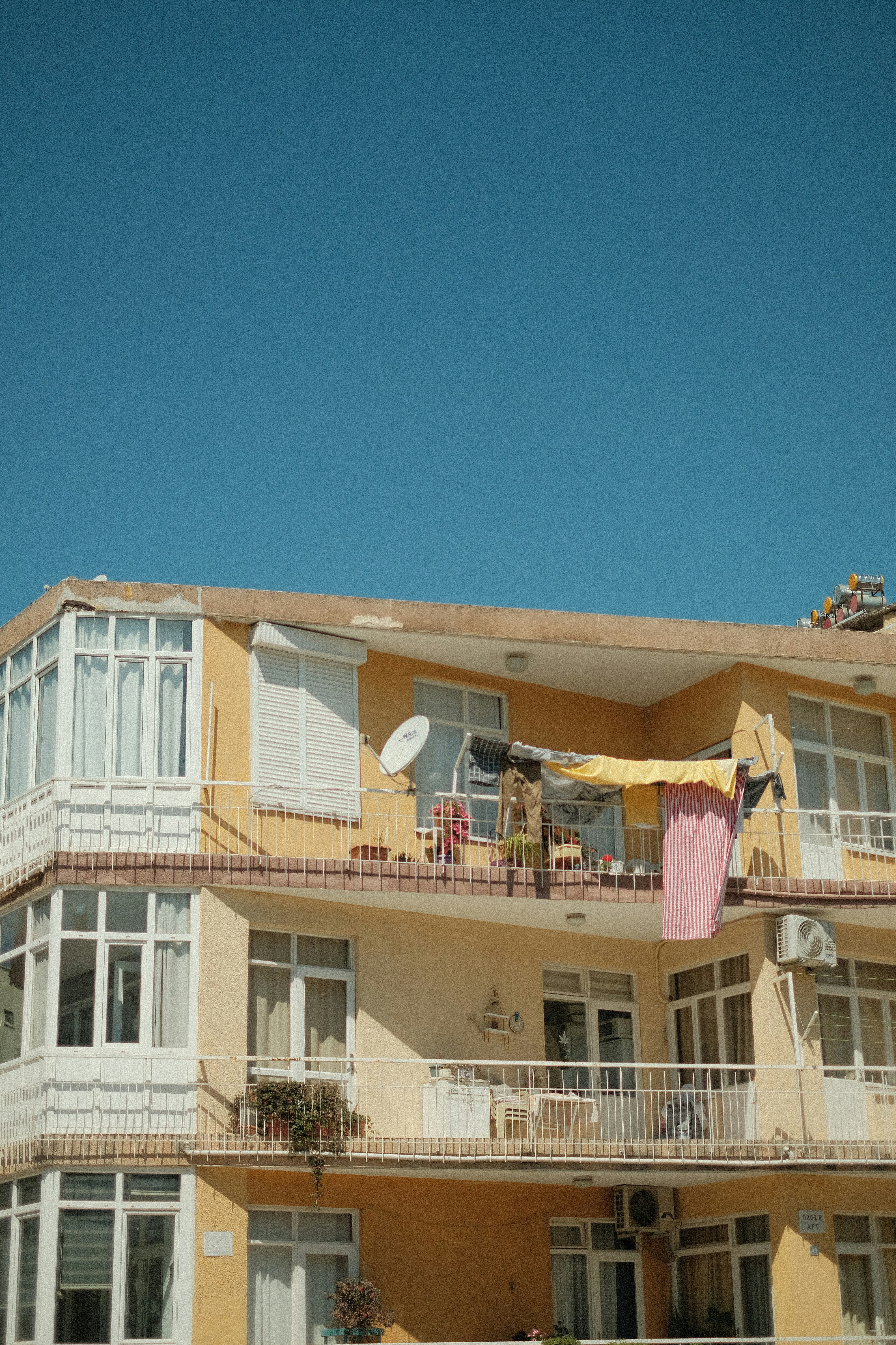 Sunlit Balcony Geometry: Yellow Apartment Block Under a Pristine Sky