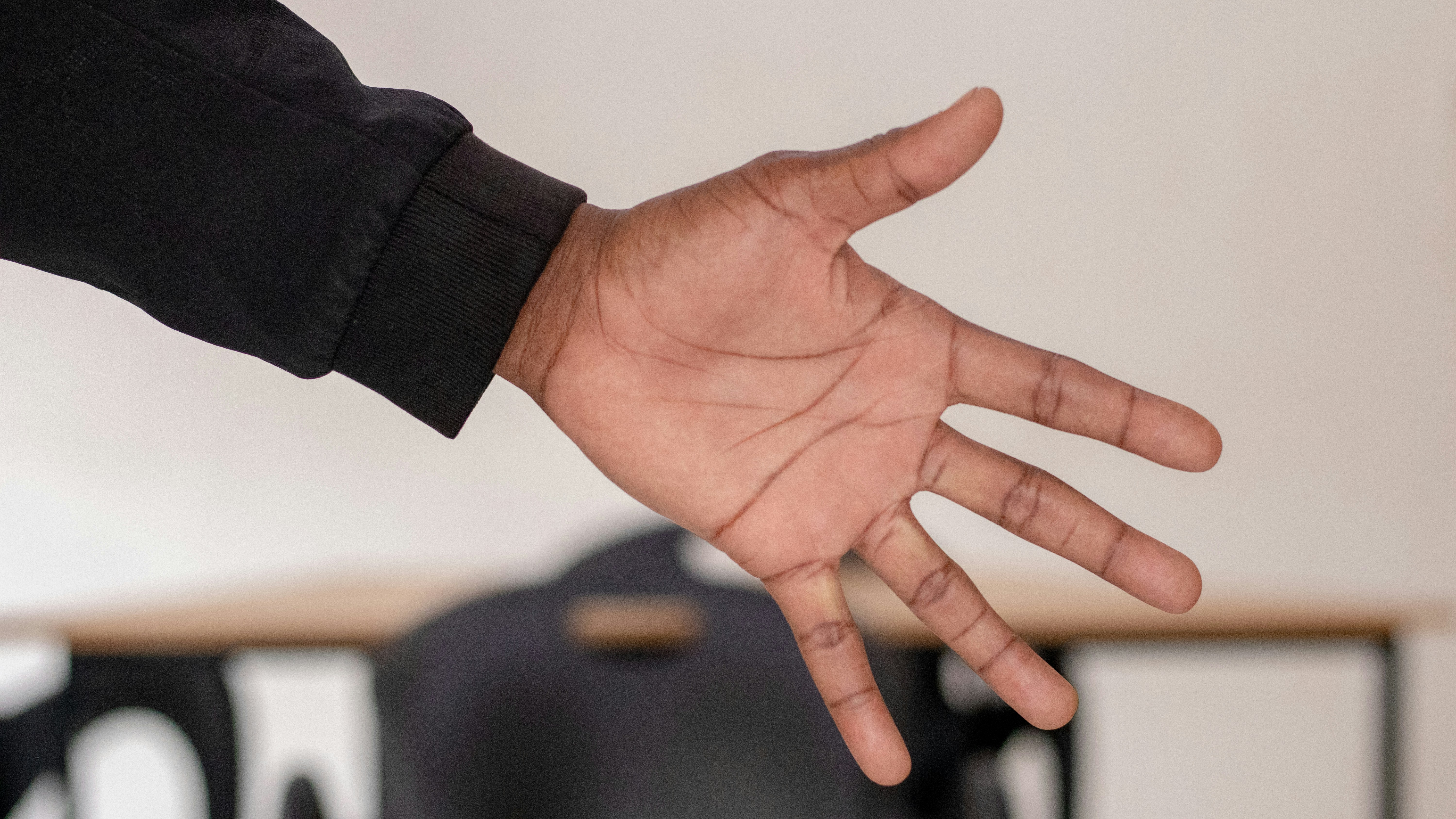 Outstretched hand against a soft-focus background in an indoor setting.