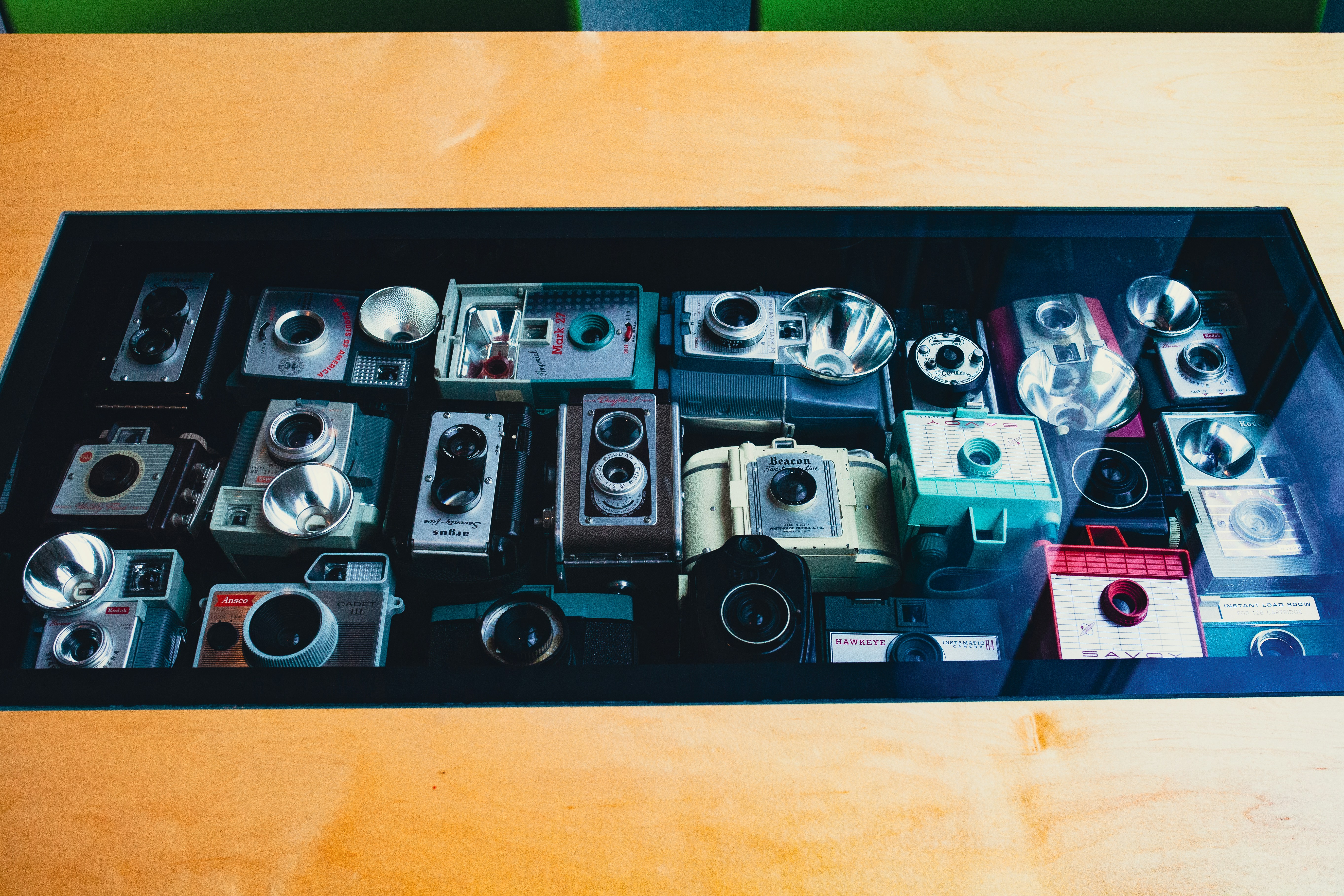 Collection of vintage cameras arranged under a glass tabletop.