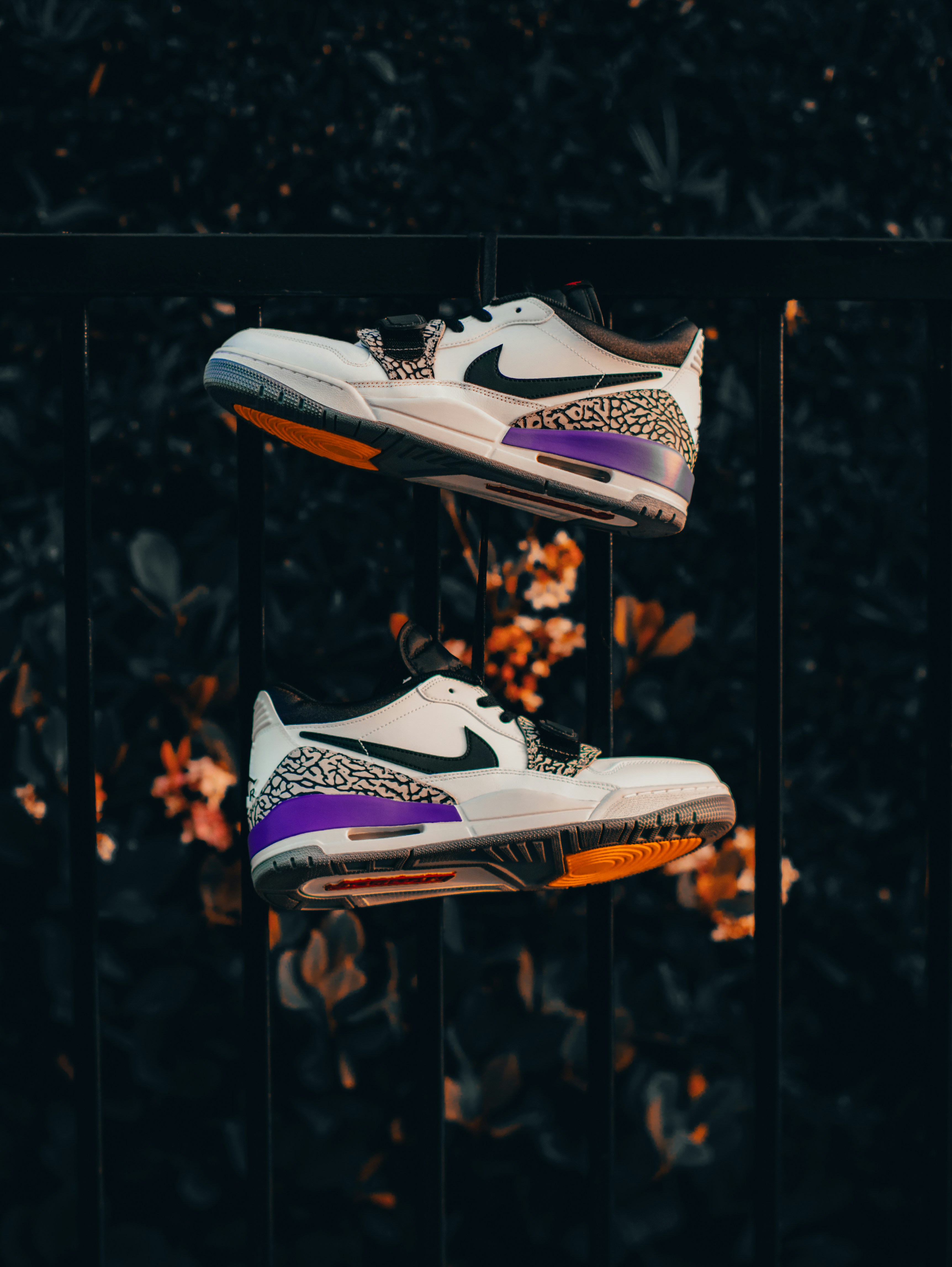Levitated Kicks: Twin Sneakers with Neon Soles on a Dark Fence