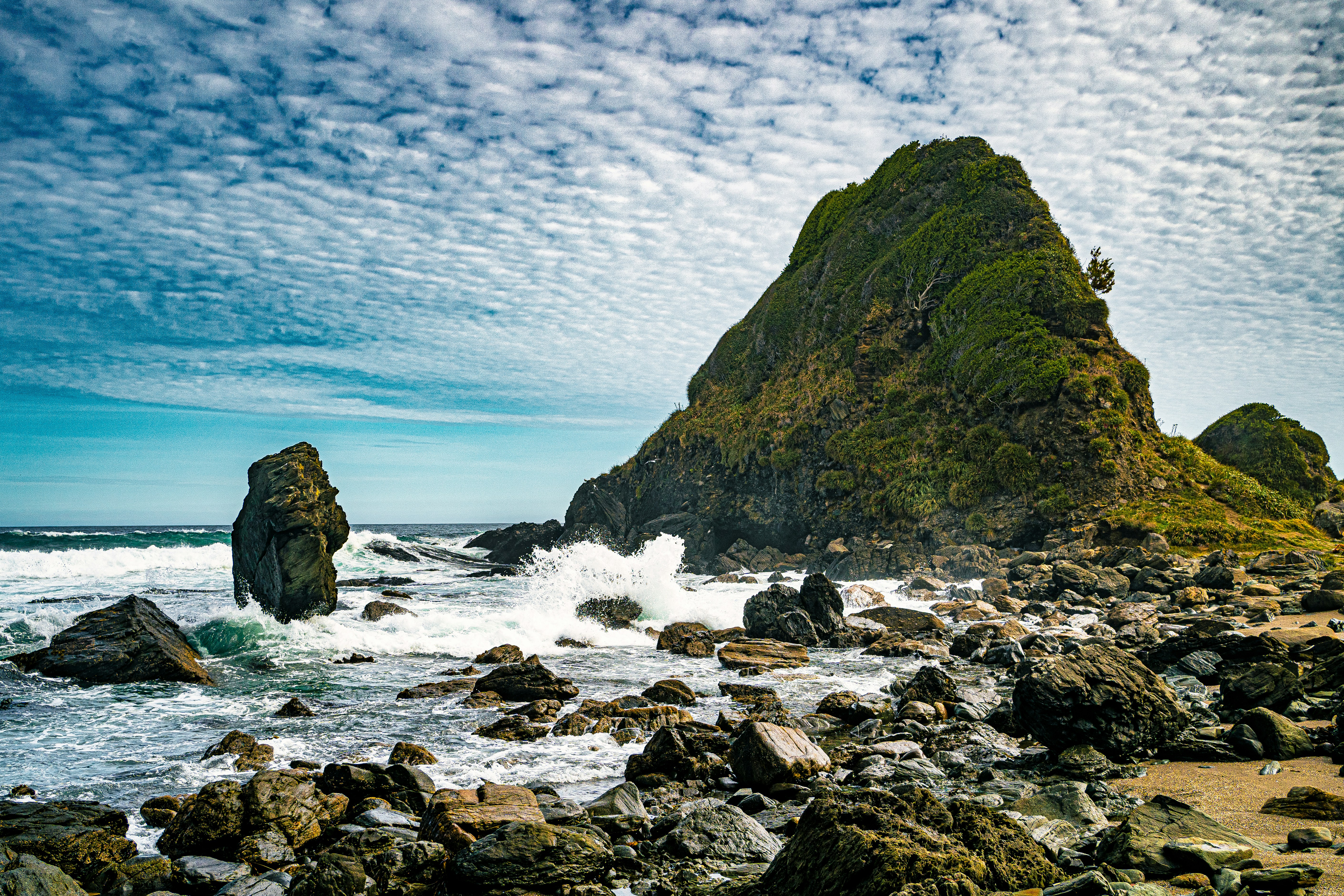 A large rock sticking out of the ocean next to a beach photo – Free ...