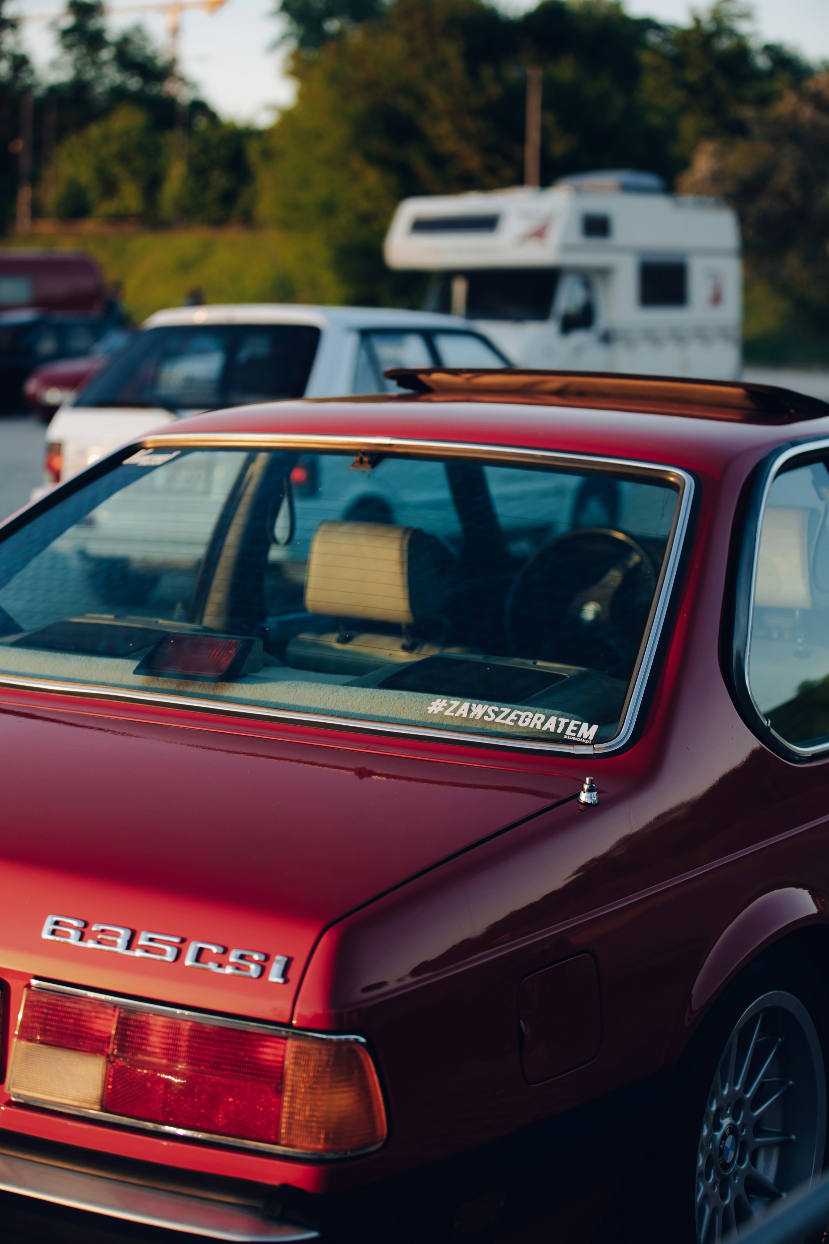 Maroon Classic: The rear quarter of a vintage BMW 626CSI at a sunlit parking lot