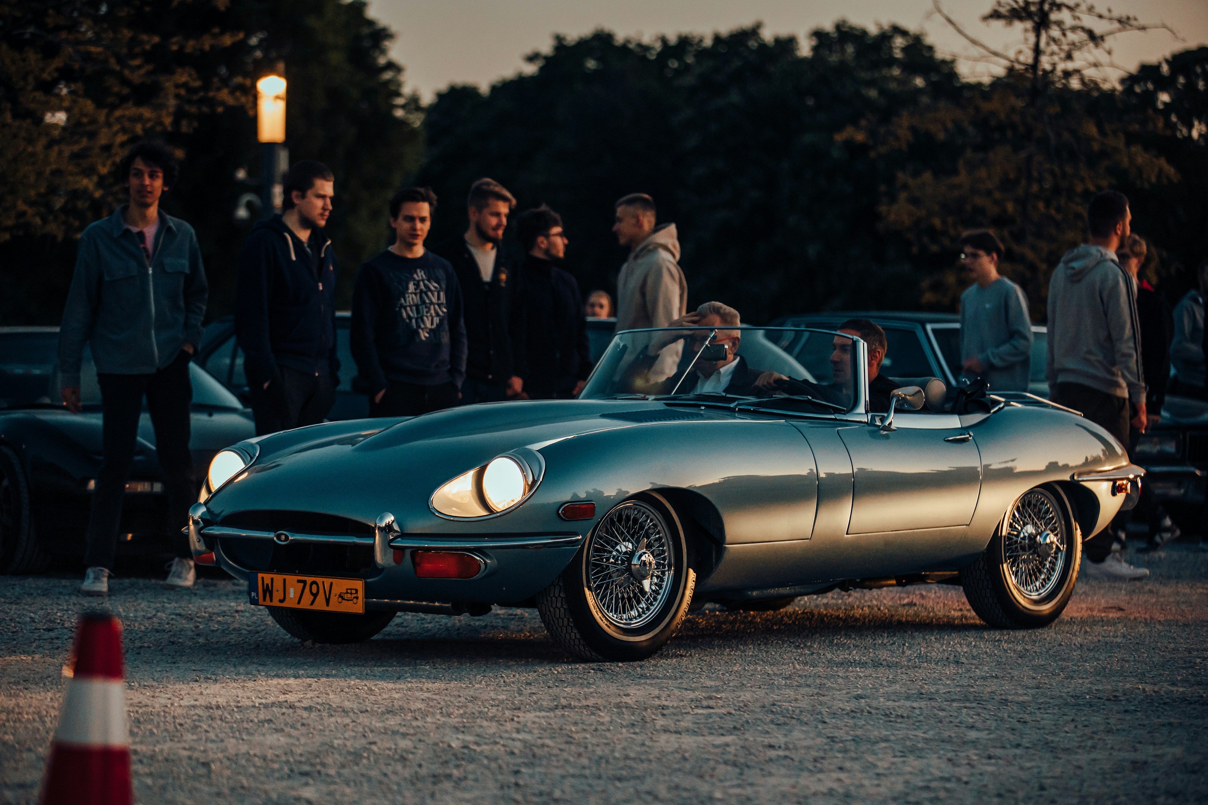 A group of people standing around a car photo – Free Jaguar Image on ...