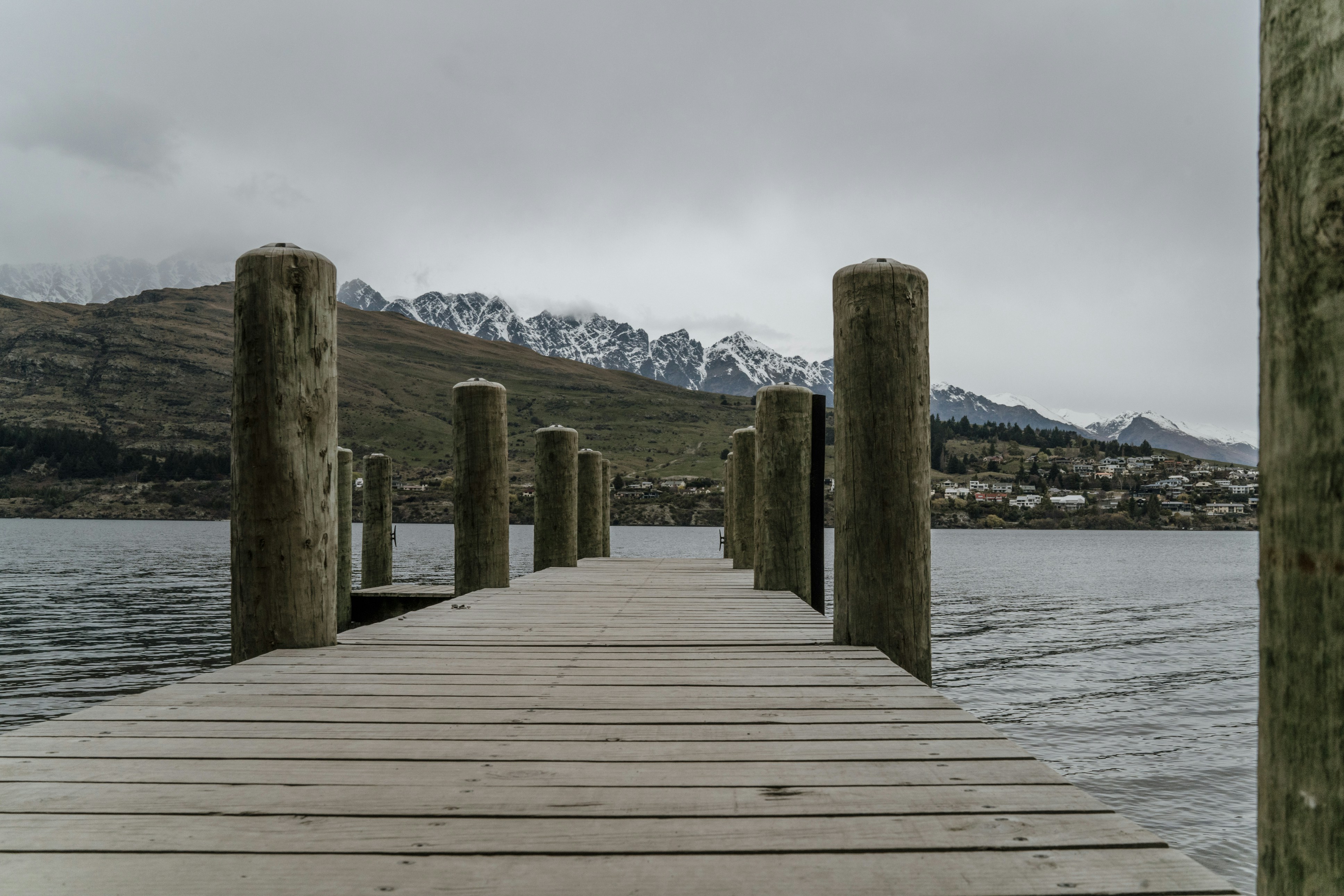 Vanishing Pier: Wooden Promenade Toward Snow-Dusted Peaks