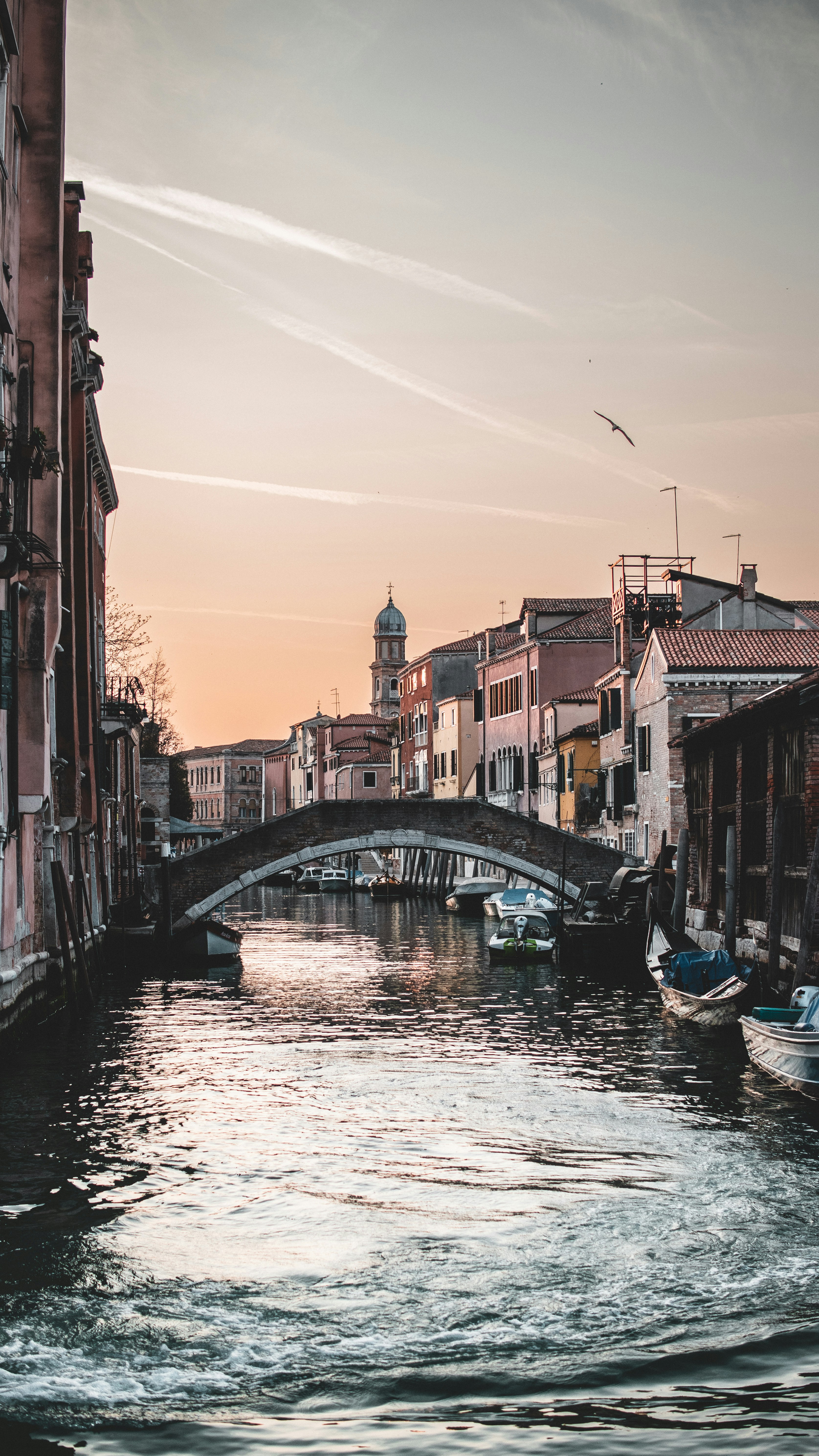 A small boat traveling down a river next to tall buildings photo – Free Venice Image on Unsplash