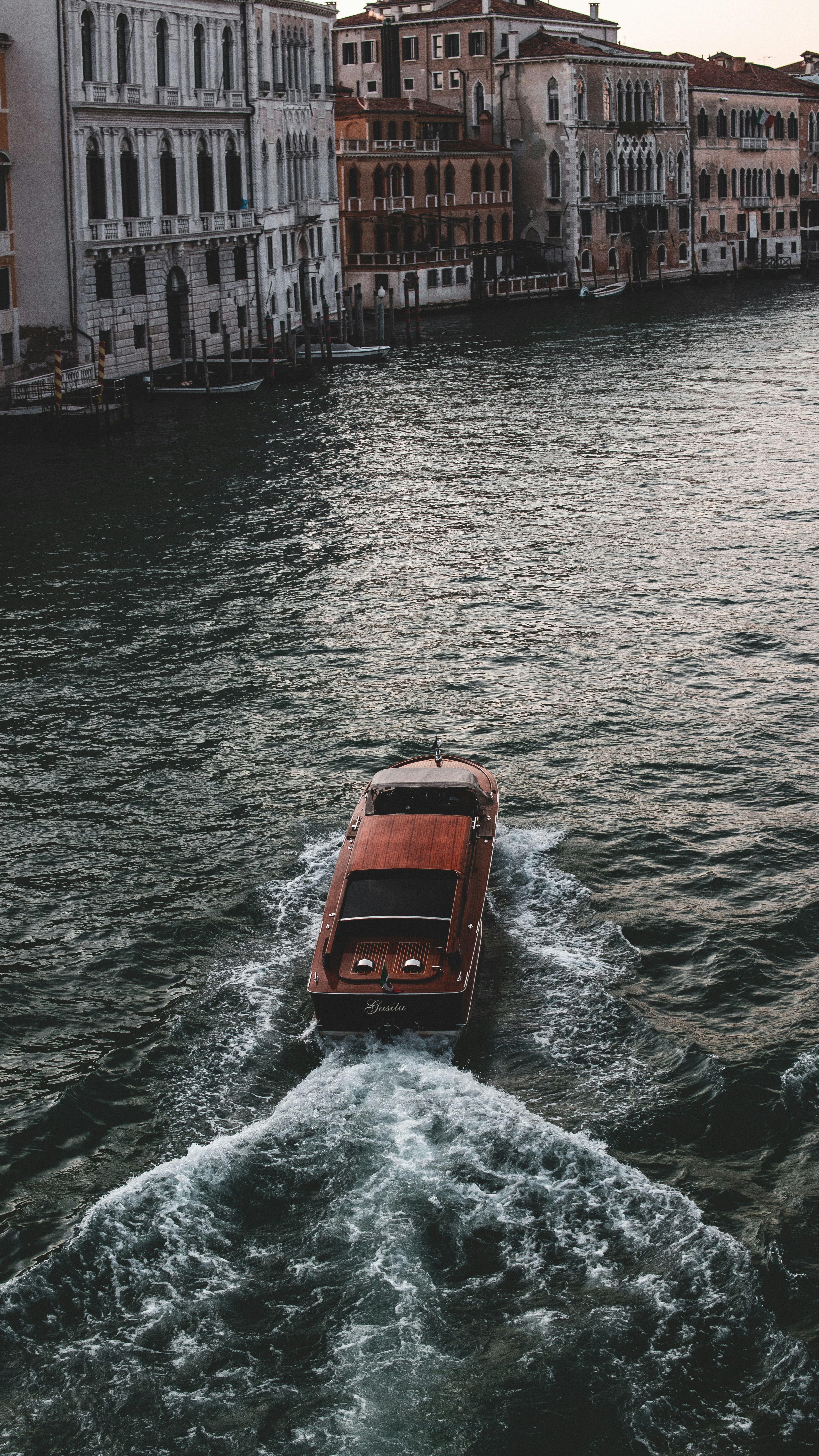 A red boat traveling down a river next to tall buildings photo – Free Wallpaper Image on Unsplash