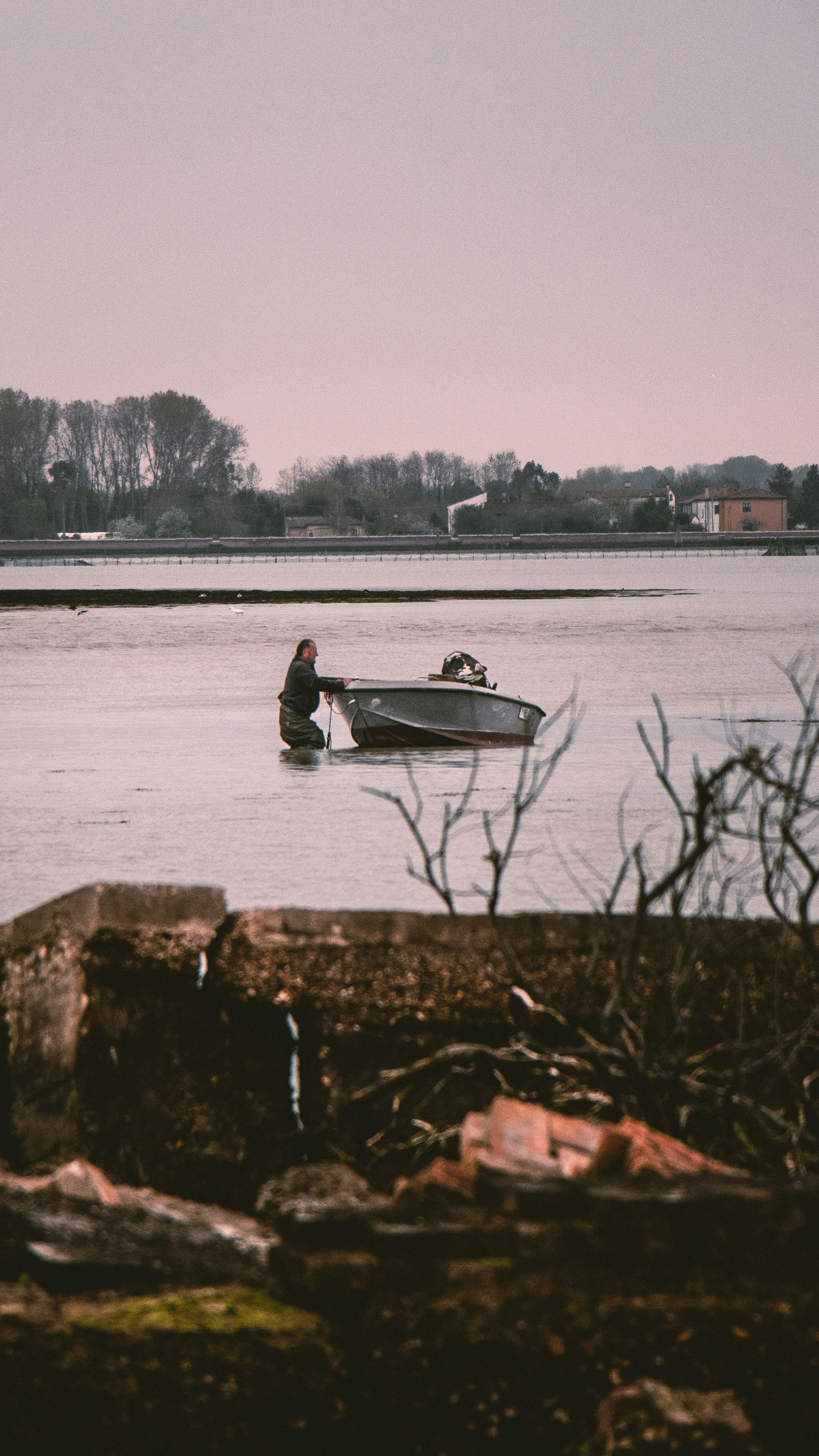 Dusk on the Quiet River: A Man Pushes a Small Boat Into the Water
