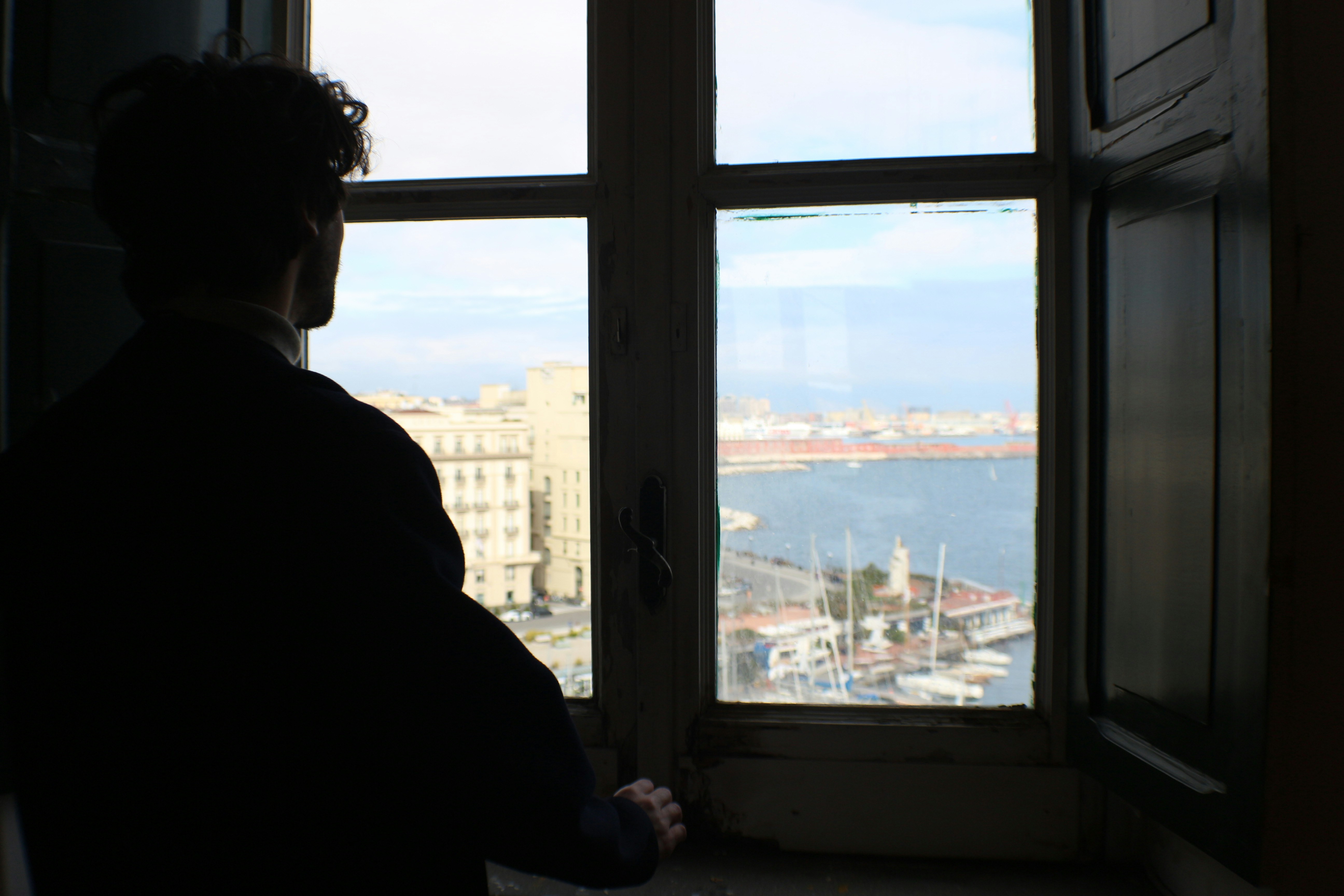 A person looking out a window at a harbor photo – Free Napoli Image on ...