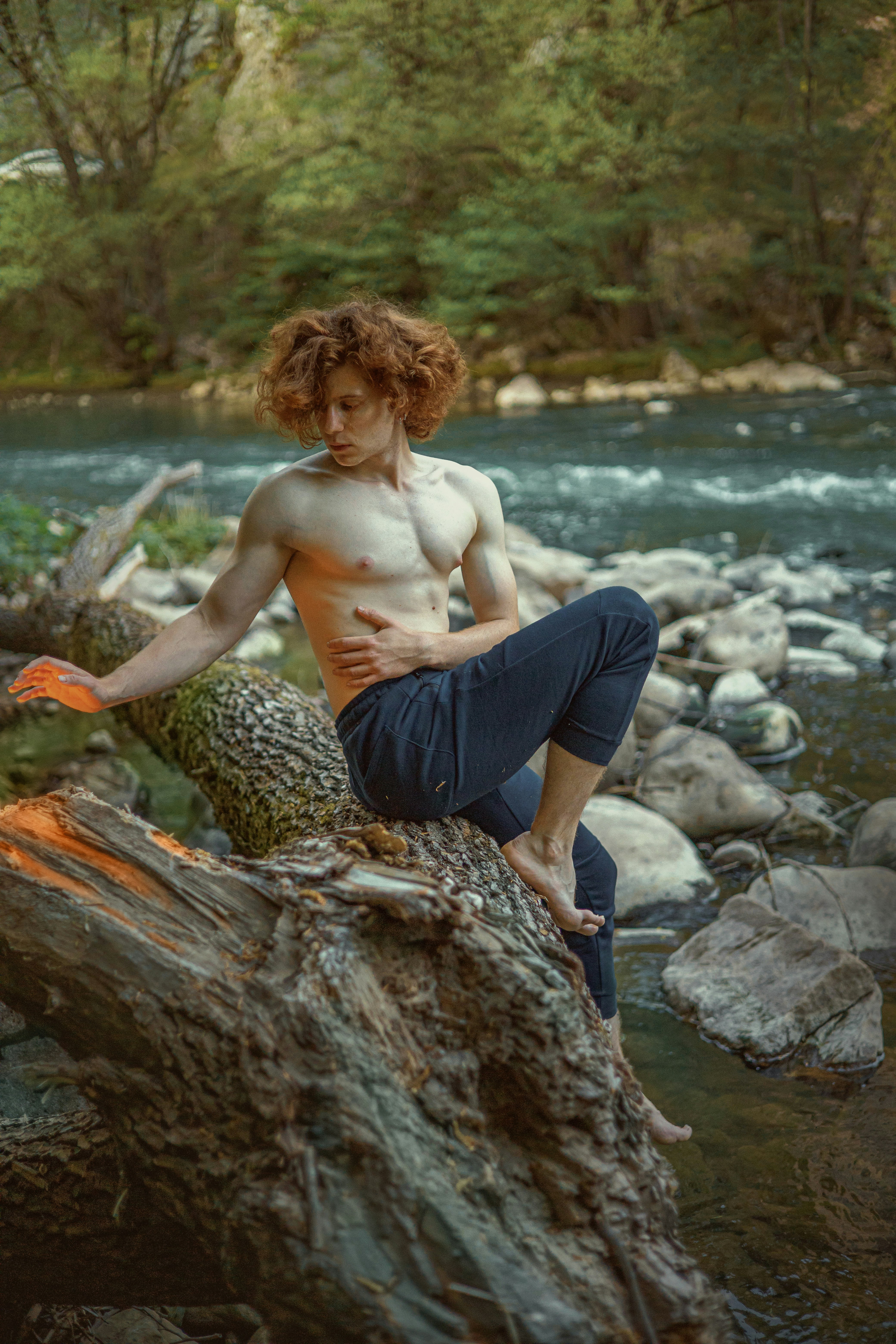 Transient Balance: a shirtless wanderer perched on a river-worn log