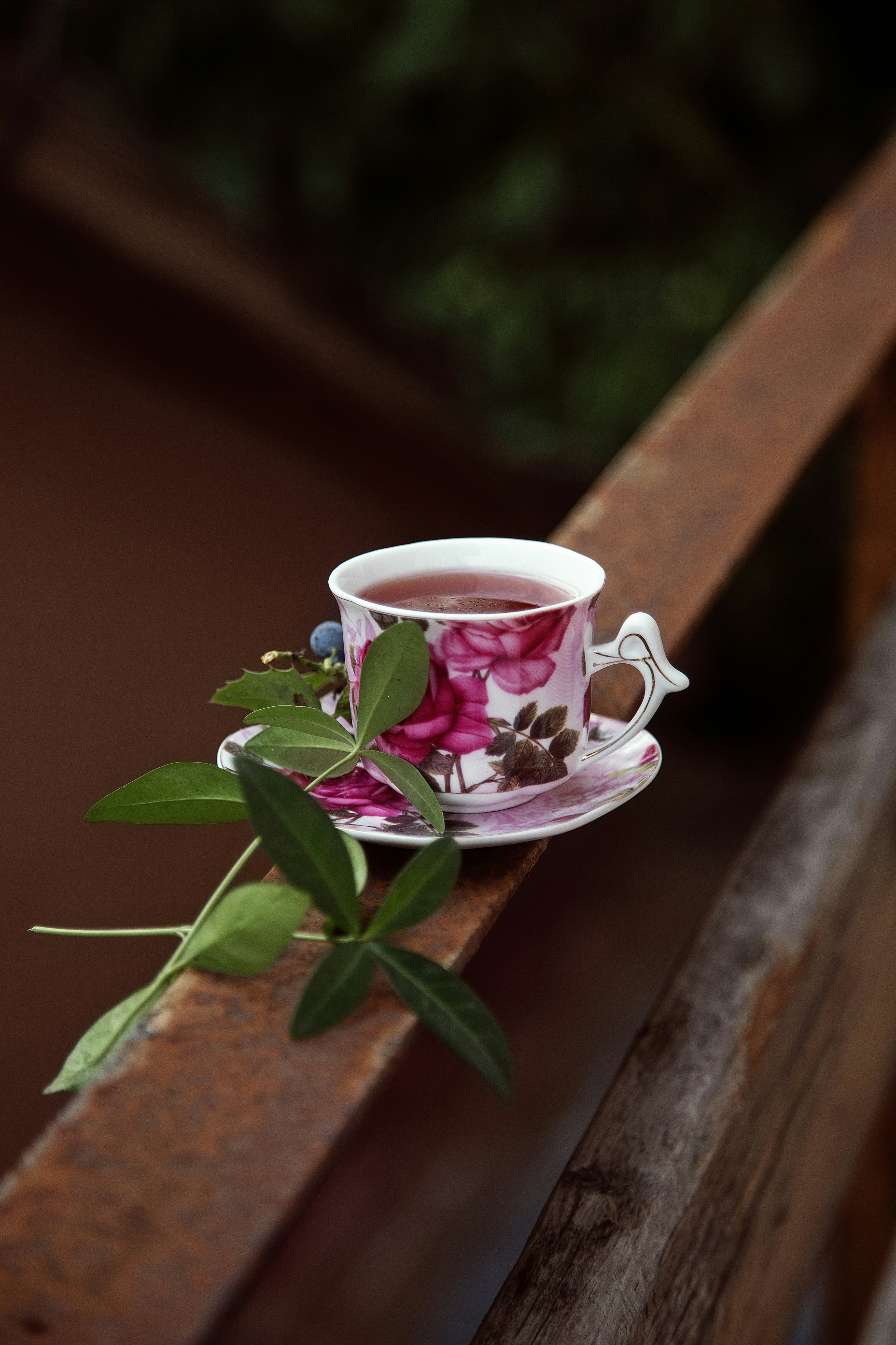 Porcelain on Rust: Teacup with Greenery on a Weathered Railing