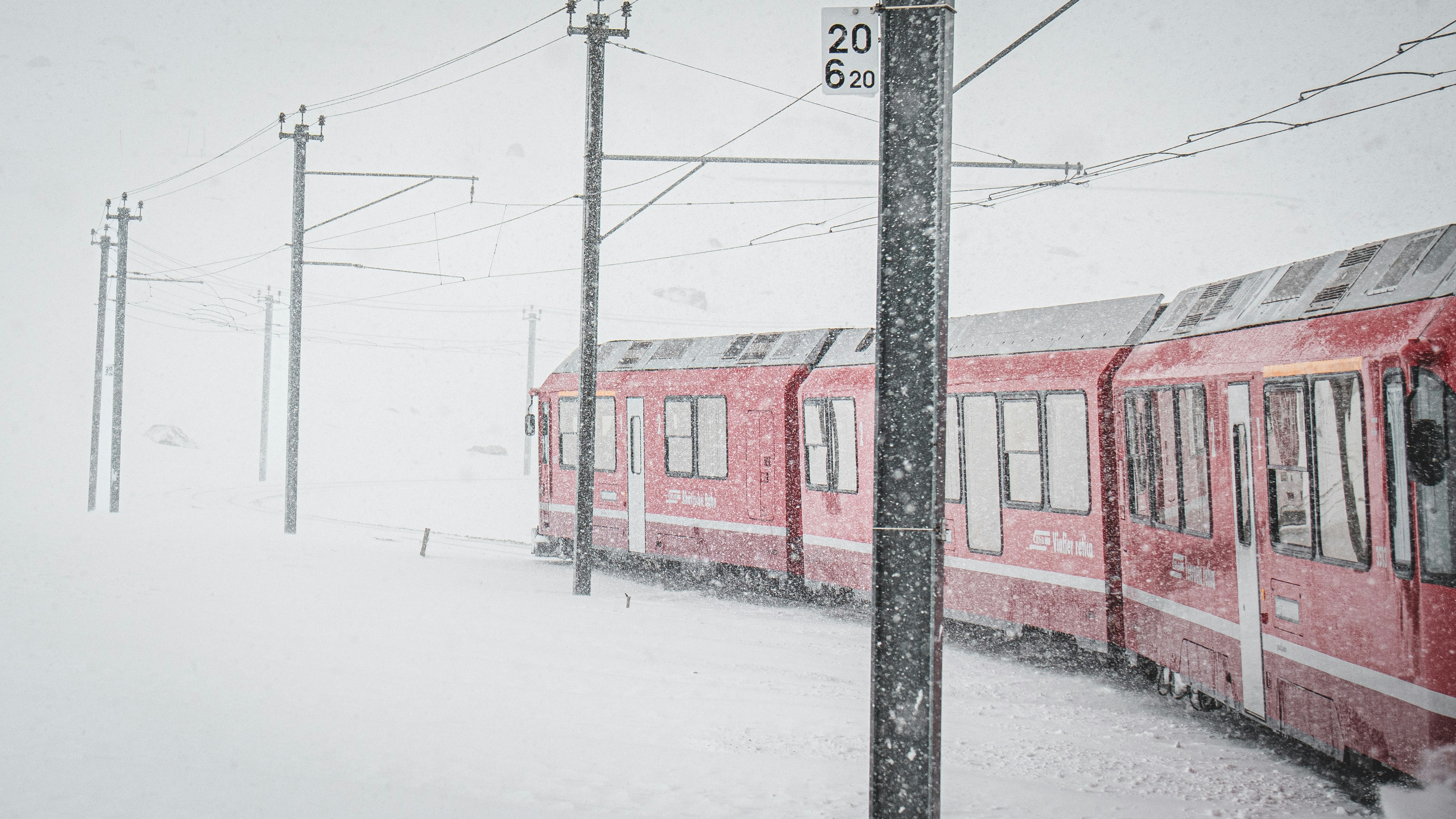 A red train traveling down train tracks covered in snow photo – Free ...