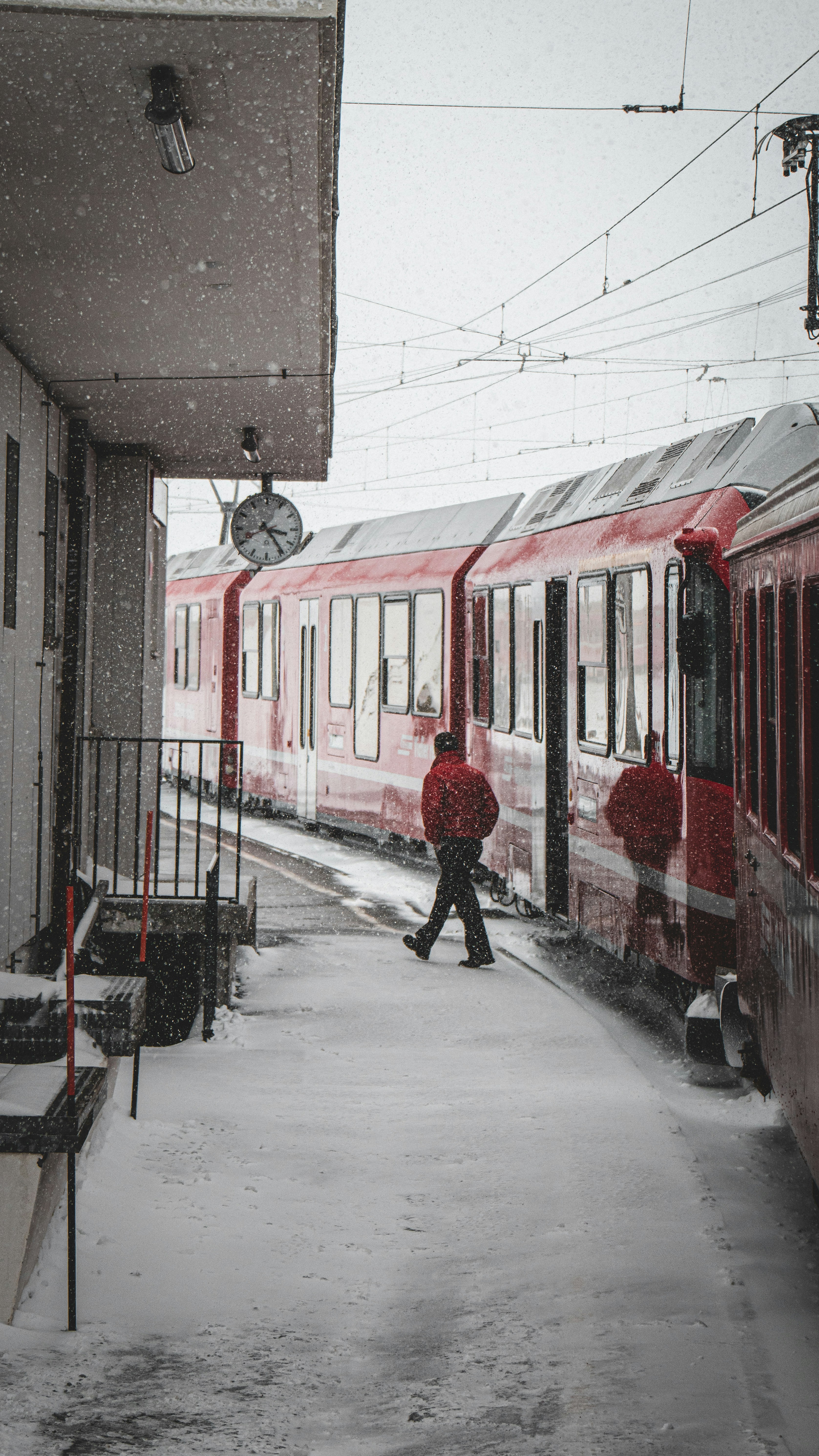 Crimson stride on a snow-dusted platform beside a red train