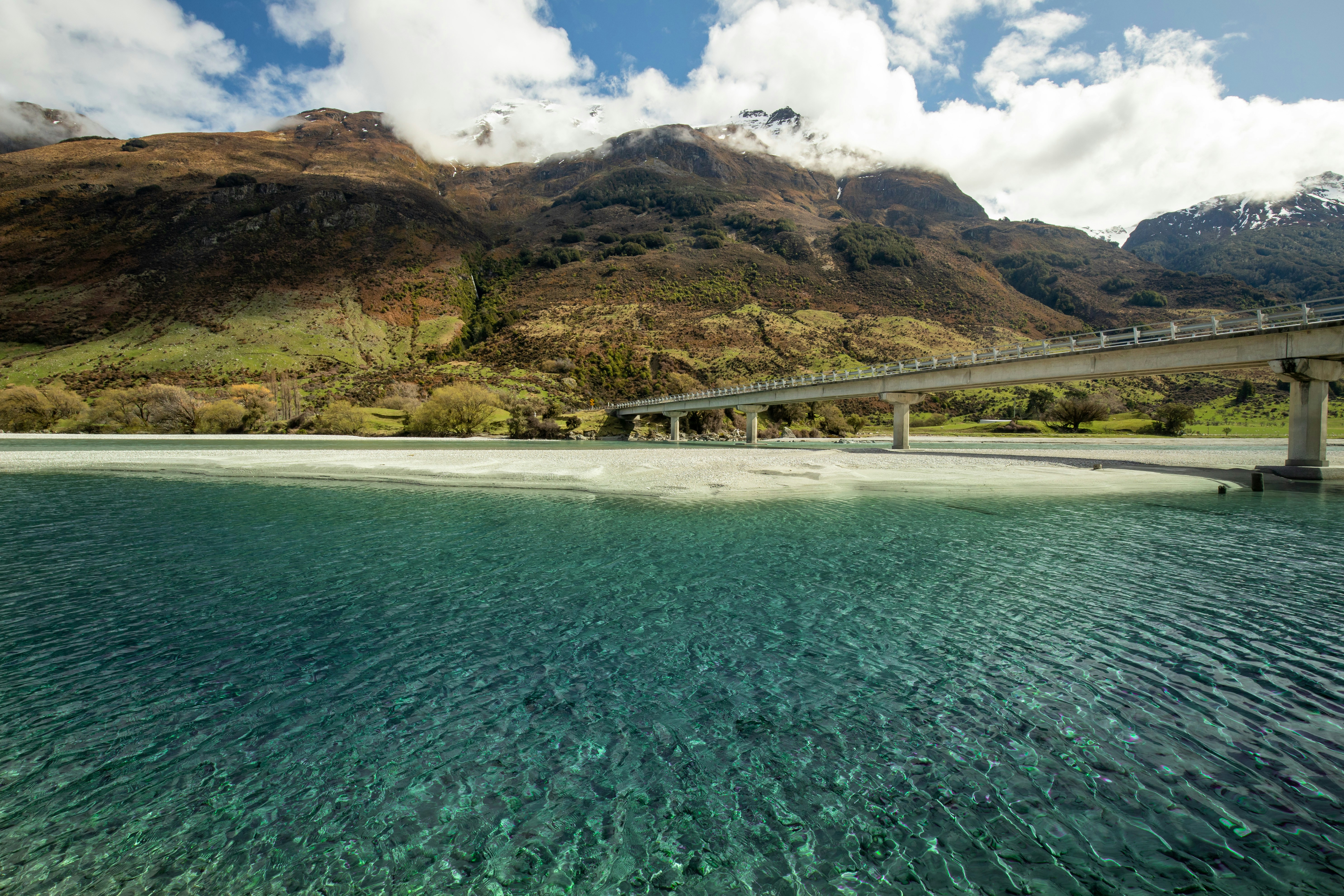 Bridge over turquoise tidal flats under a rugged coastline
