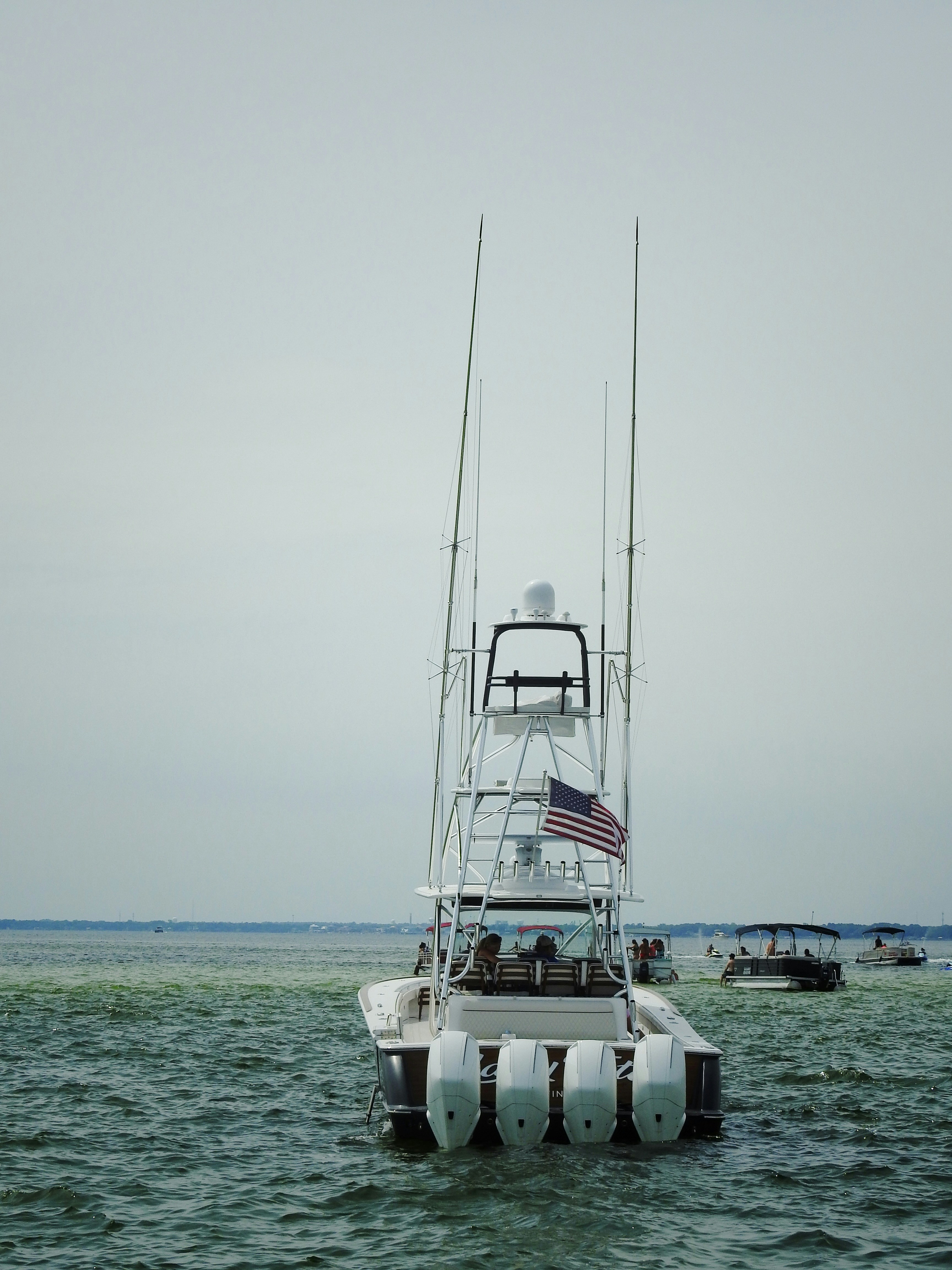 Flagged Return: The Stern of a White Offshore Vessel in Quiet Blue Waters