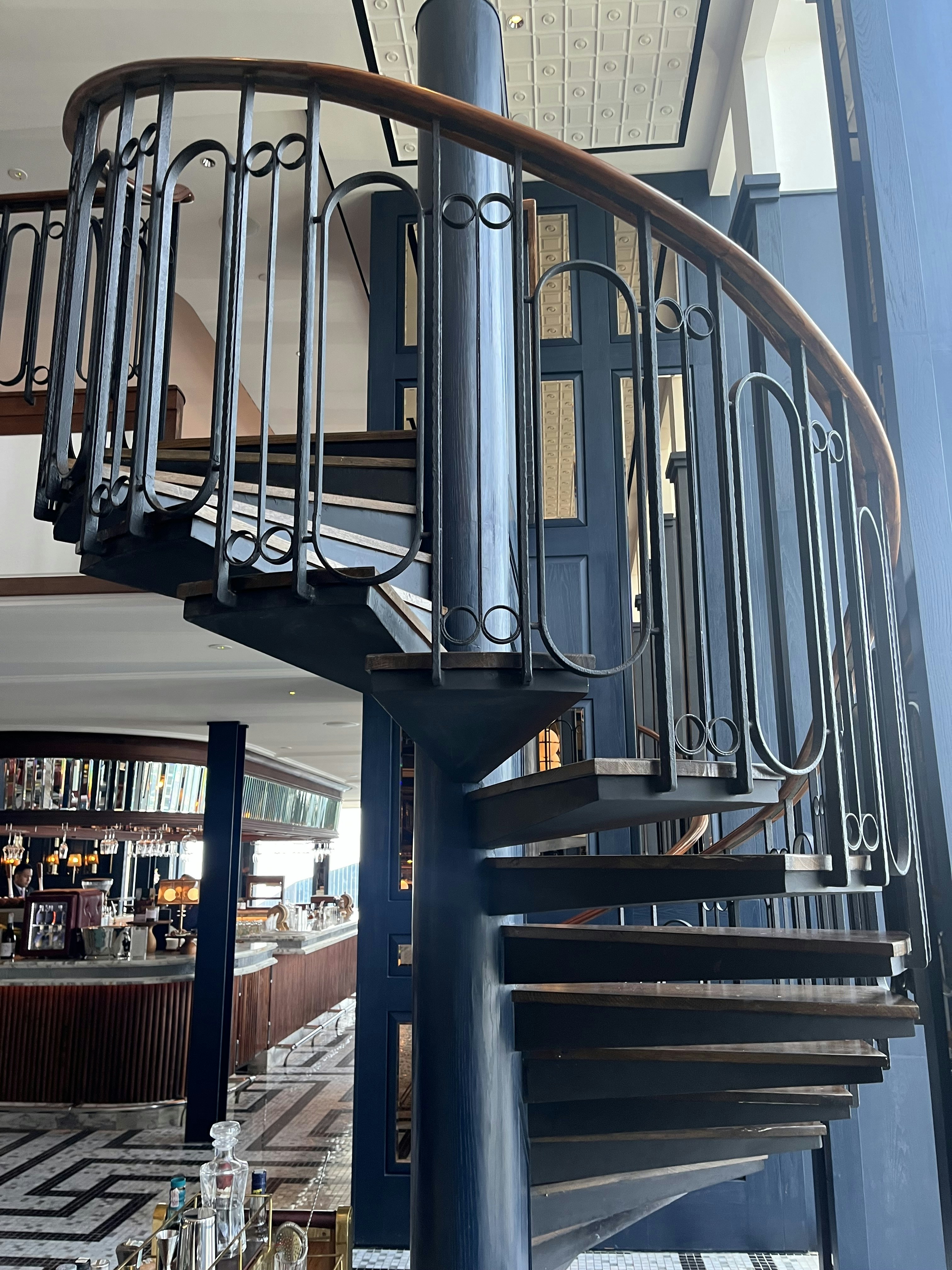A spiral staircase in a restaurant with a bar in the background photo ...
