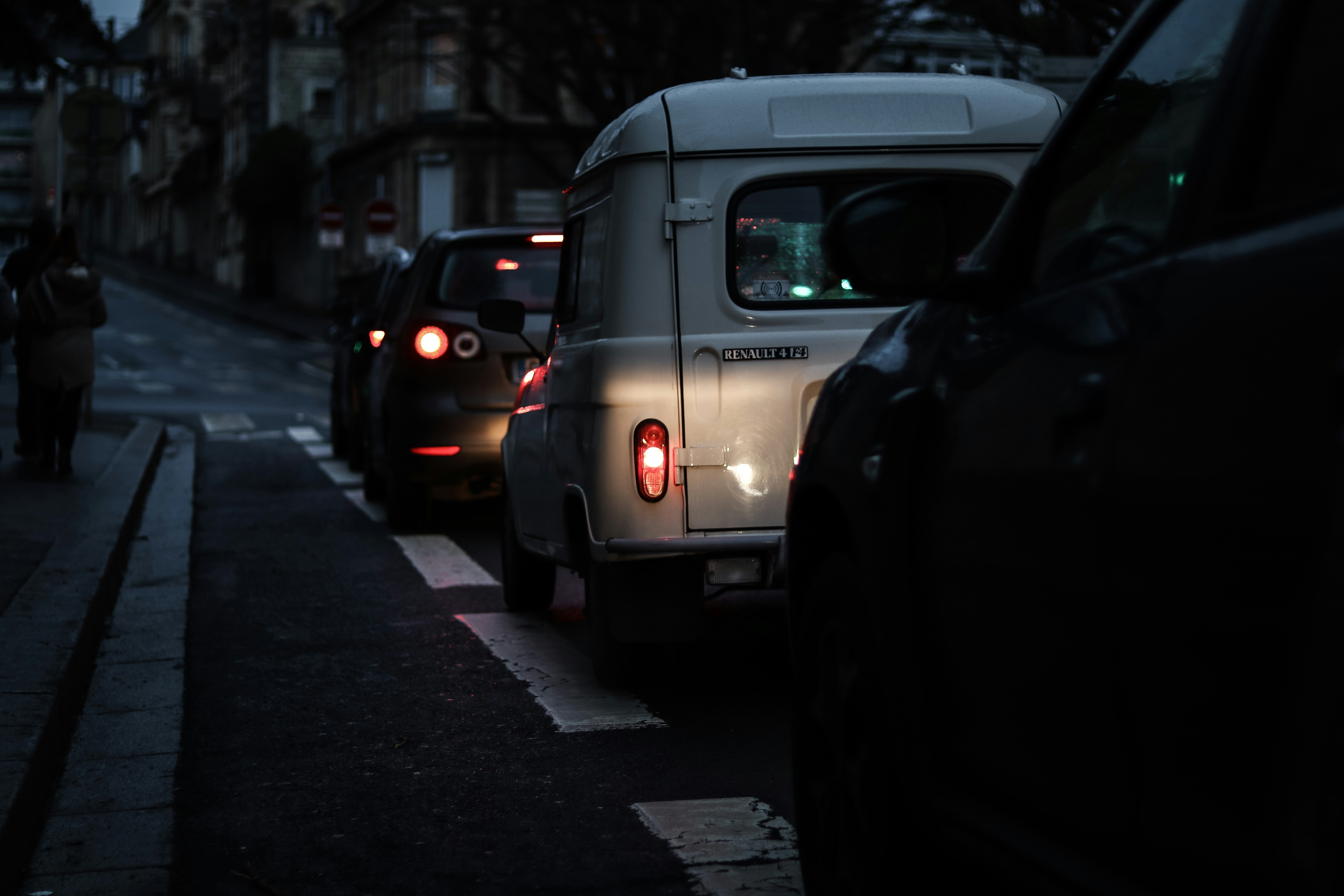 Vintage cars lined up on a dimly lit street during dusk.