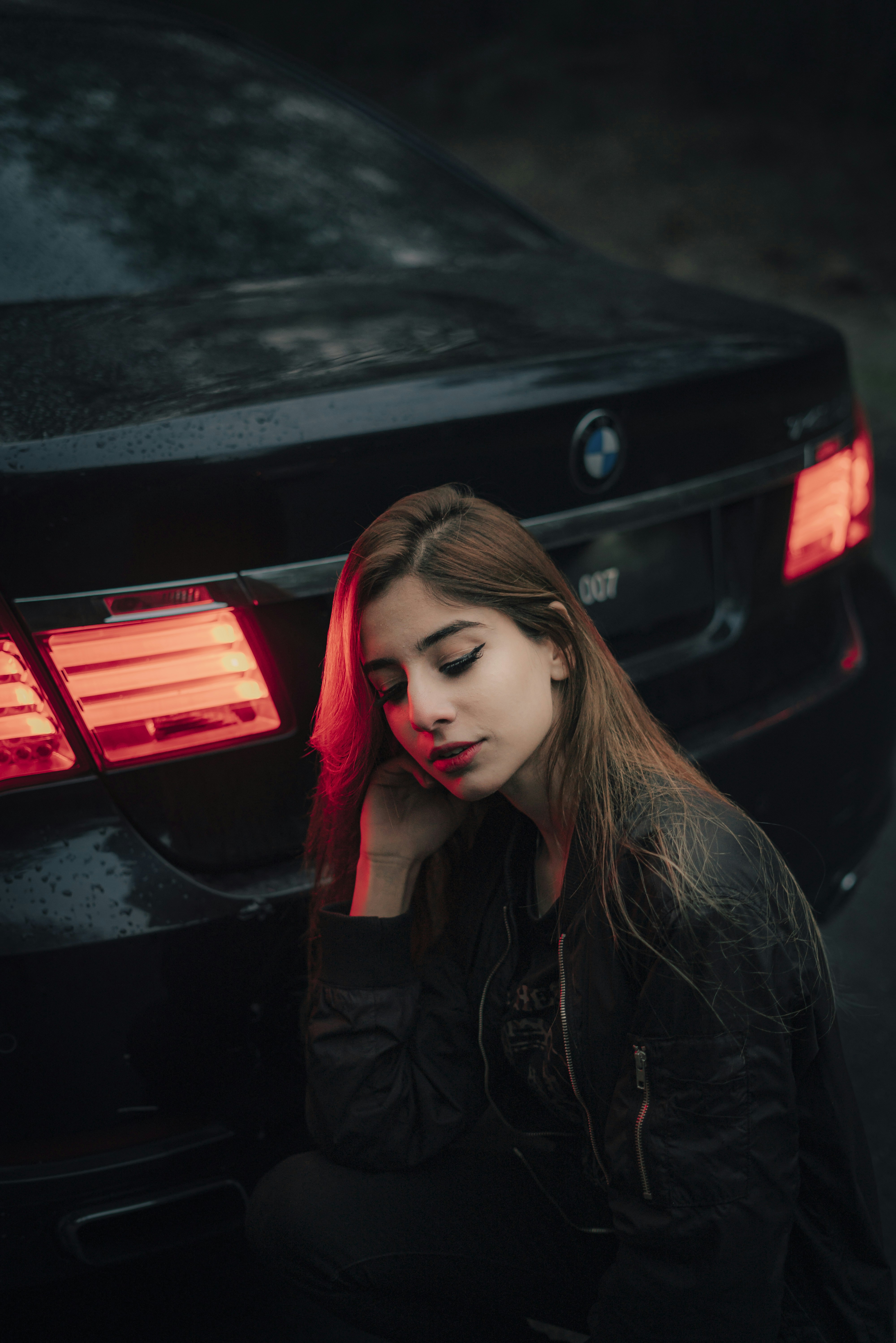 Crimson Tail Light Portrait: A Quiet Moment Beside a Black BMW