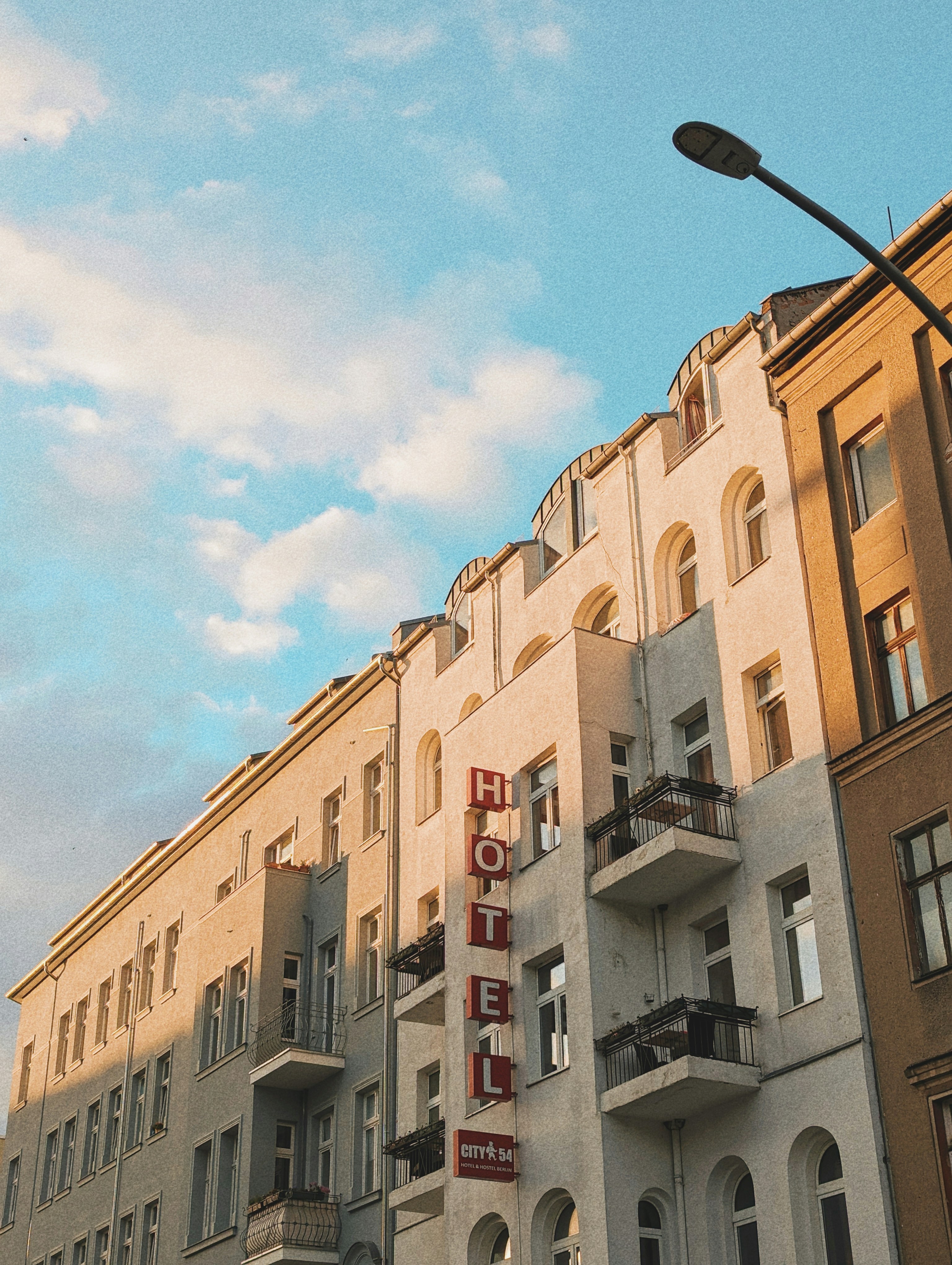 Vertical Hotel Sign Against a Sunlit Facade Under a Clear Sky