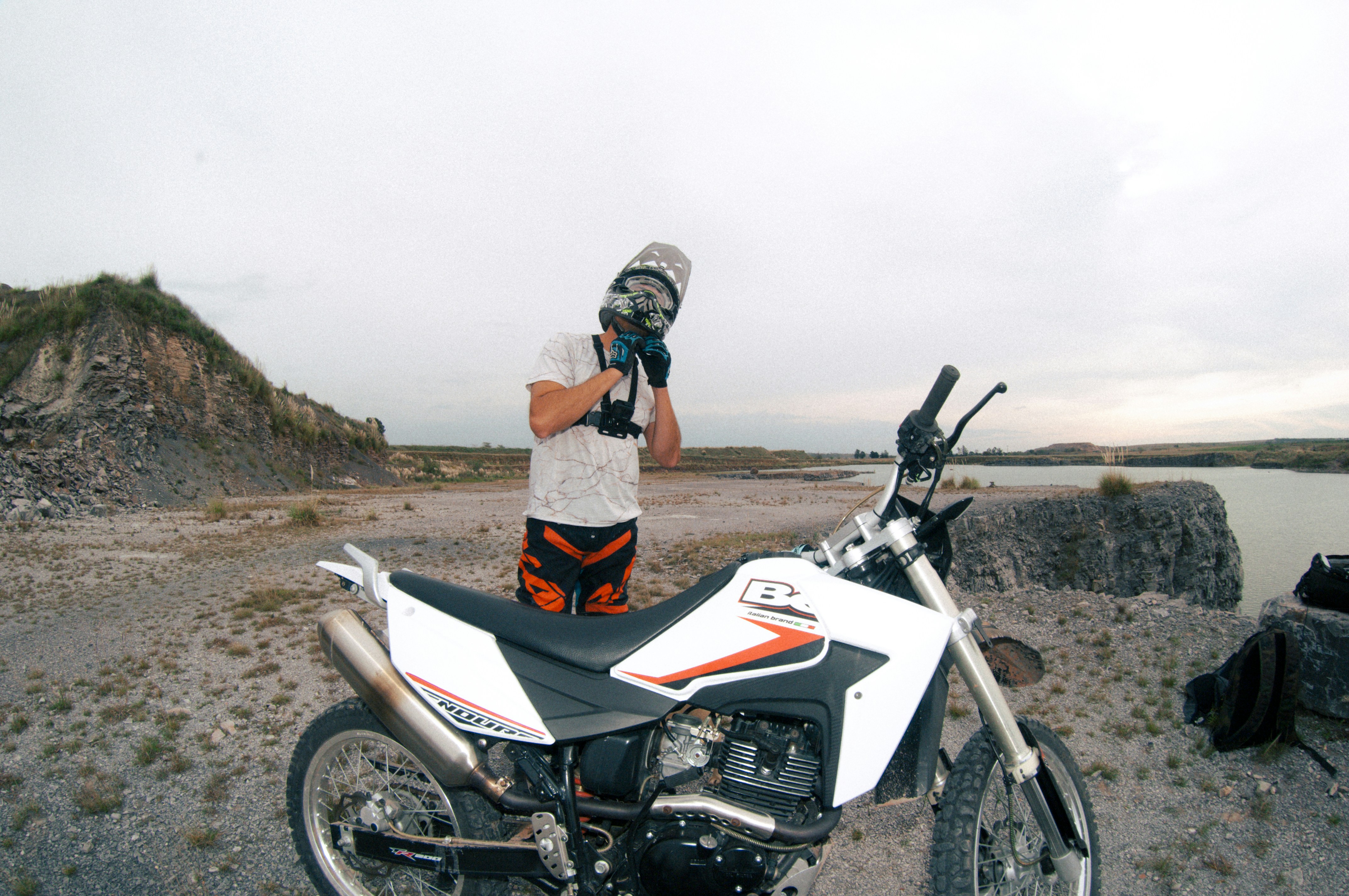 Dusty shoreline standoff: rider readying a bike silhouette at dusk