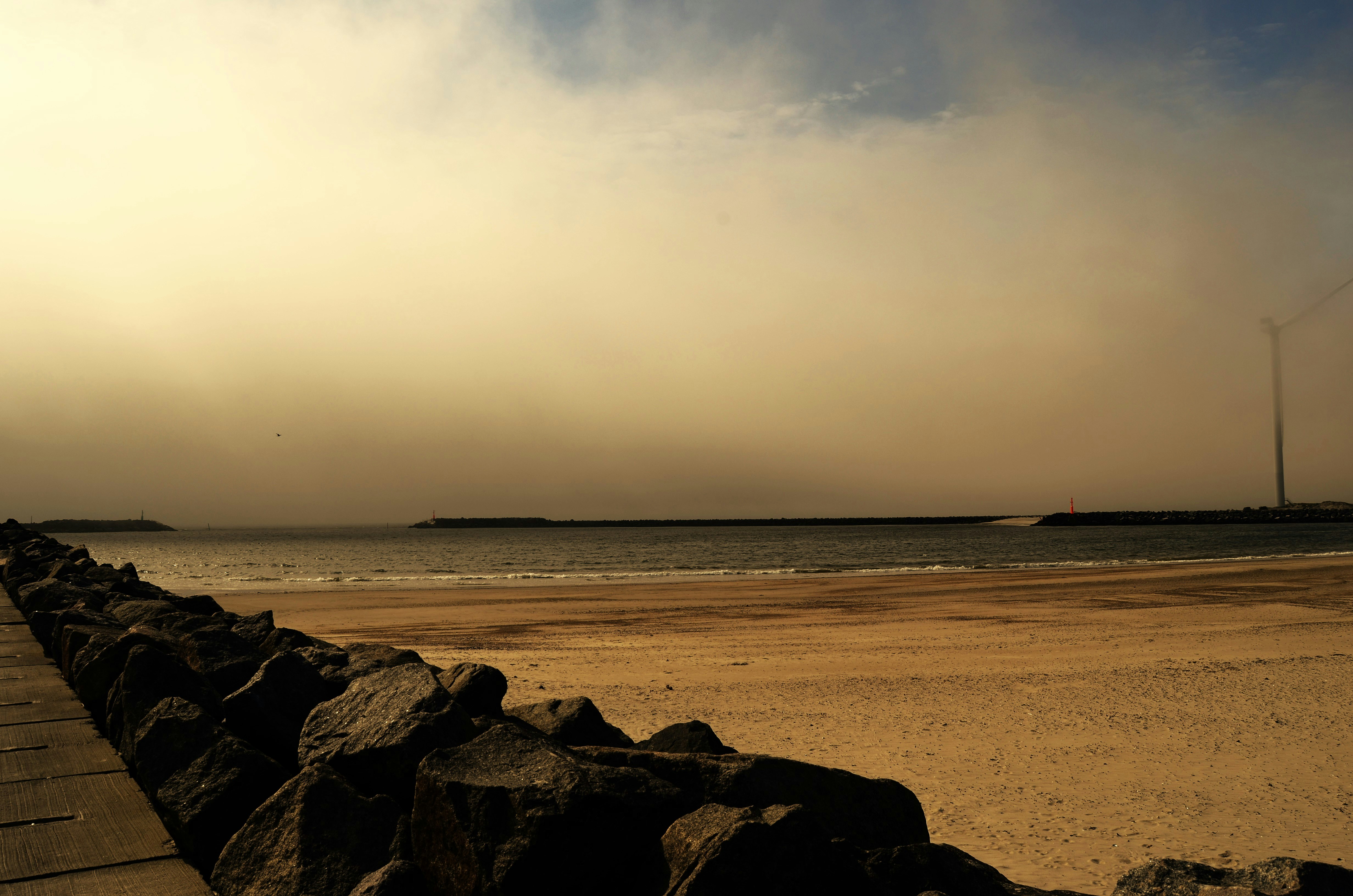 A sandy beach next to the ocean under a cloudy sky photo – Free Hvide ...