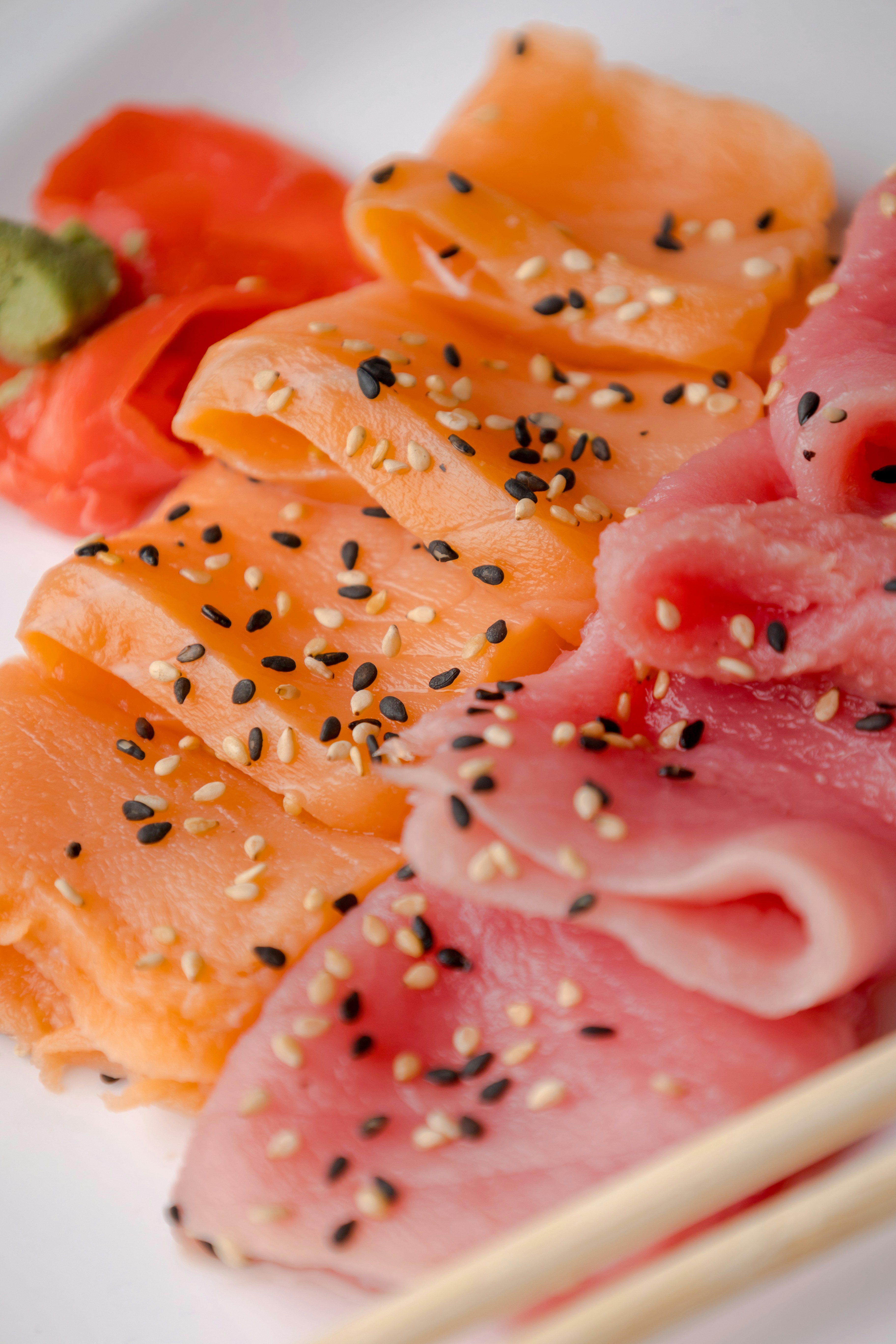 Assorted sashimi featuring vibrant slices of salmon and tuna, garnished with sesame seeds and wasabi. Perfectly arranged for an appetizing presentation.