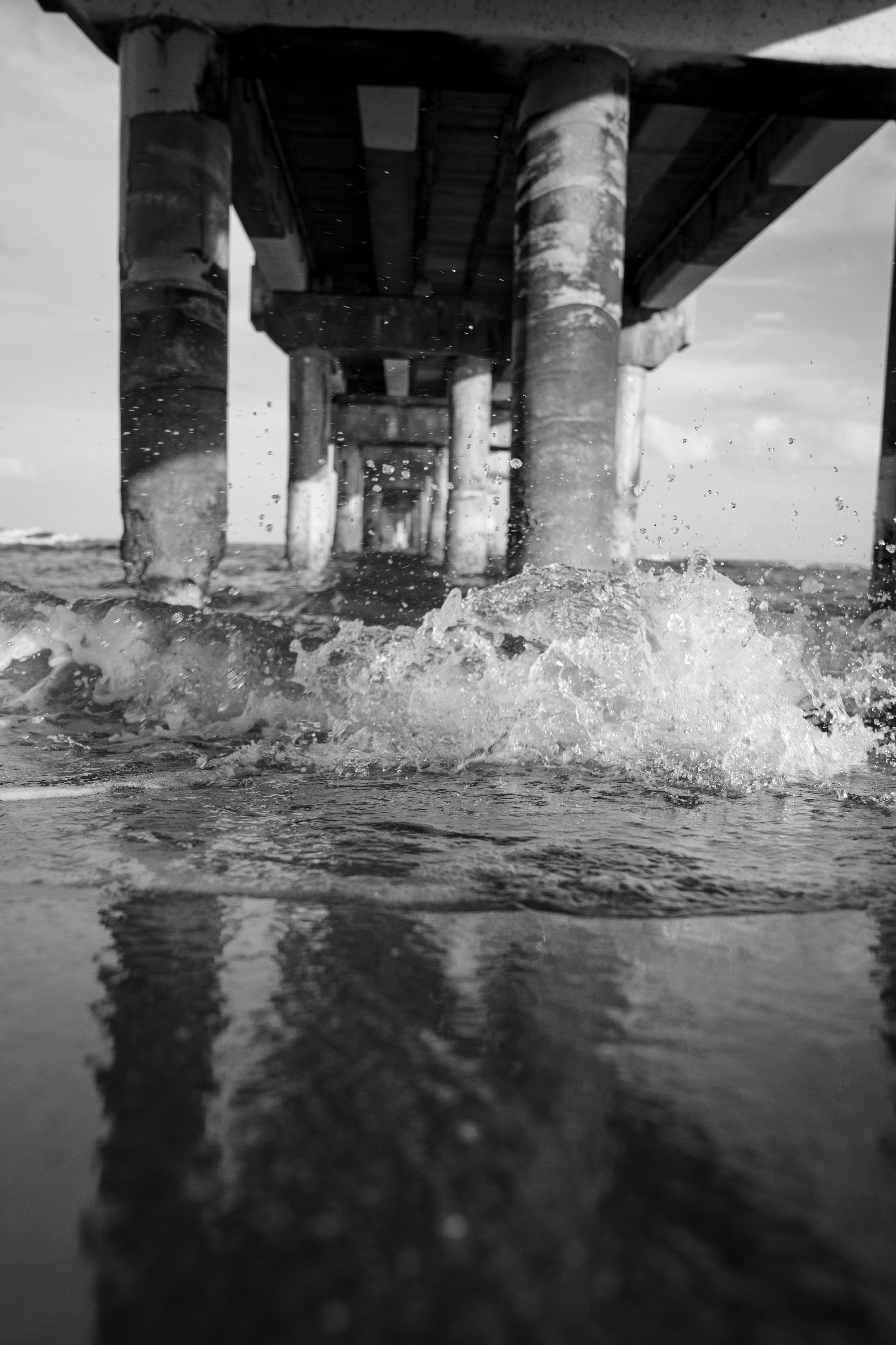Under the Pier: a Monochrome Corridor of Columns Enveloped by Cresting Wake