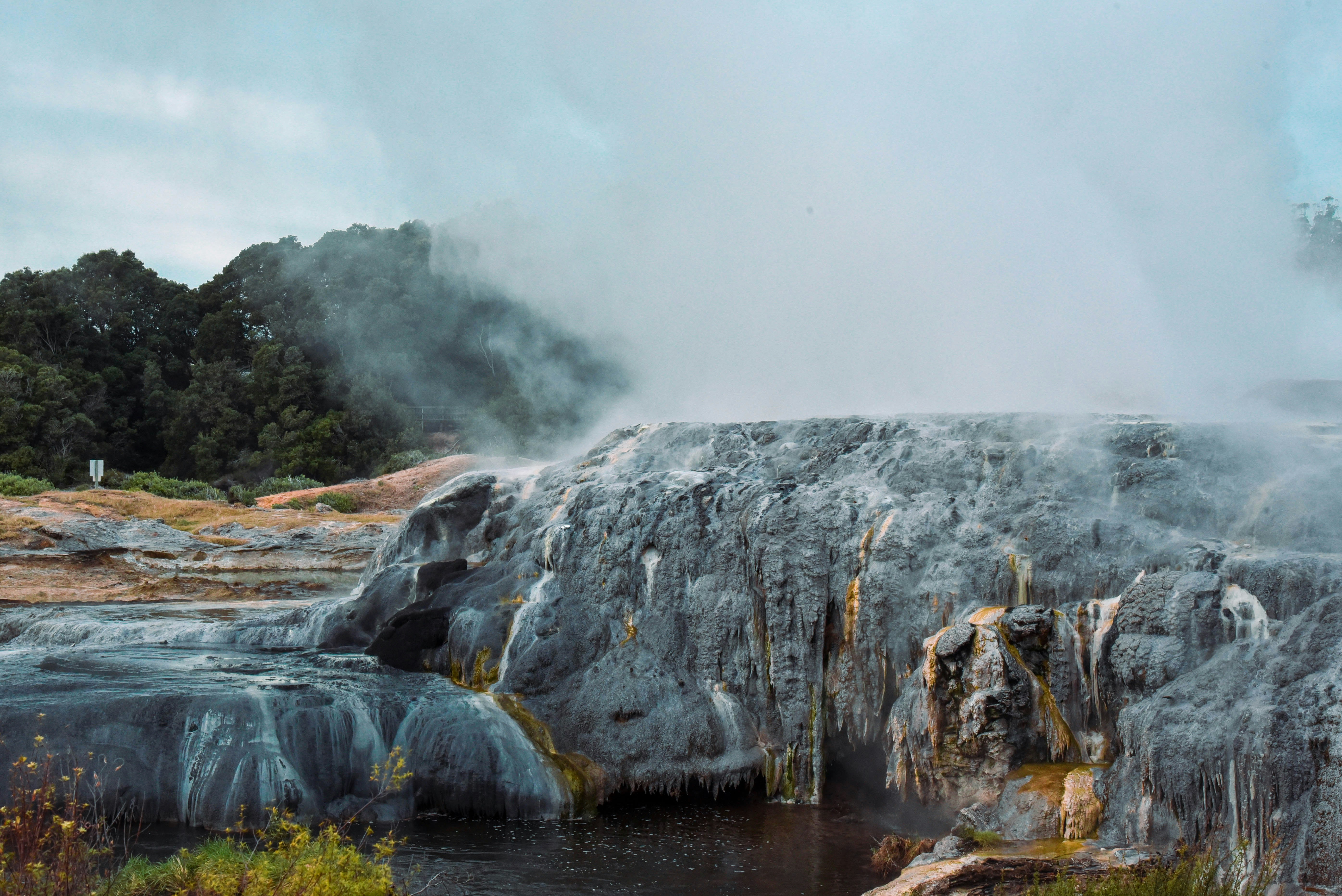 A geyser spewing water into a river surrounded by rocks photo – Free ...