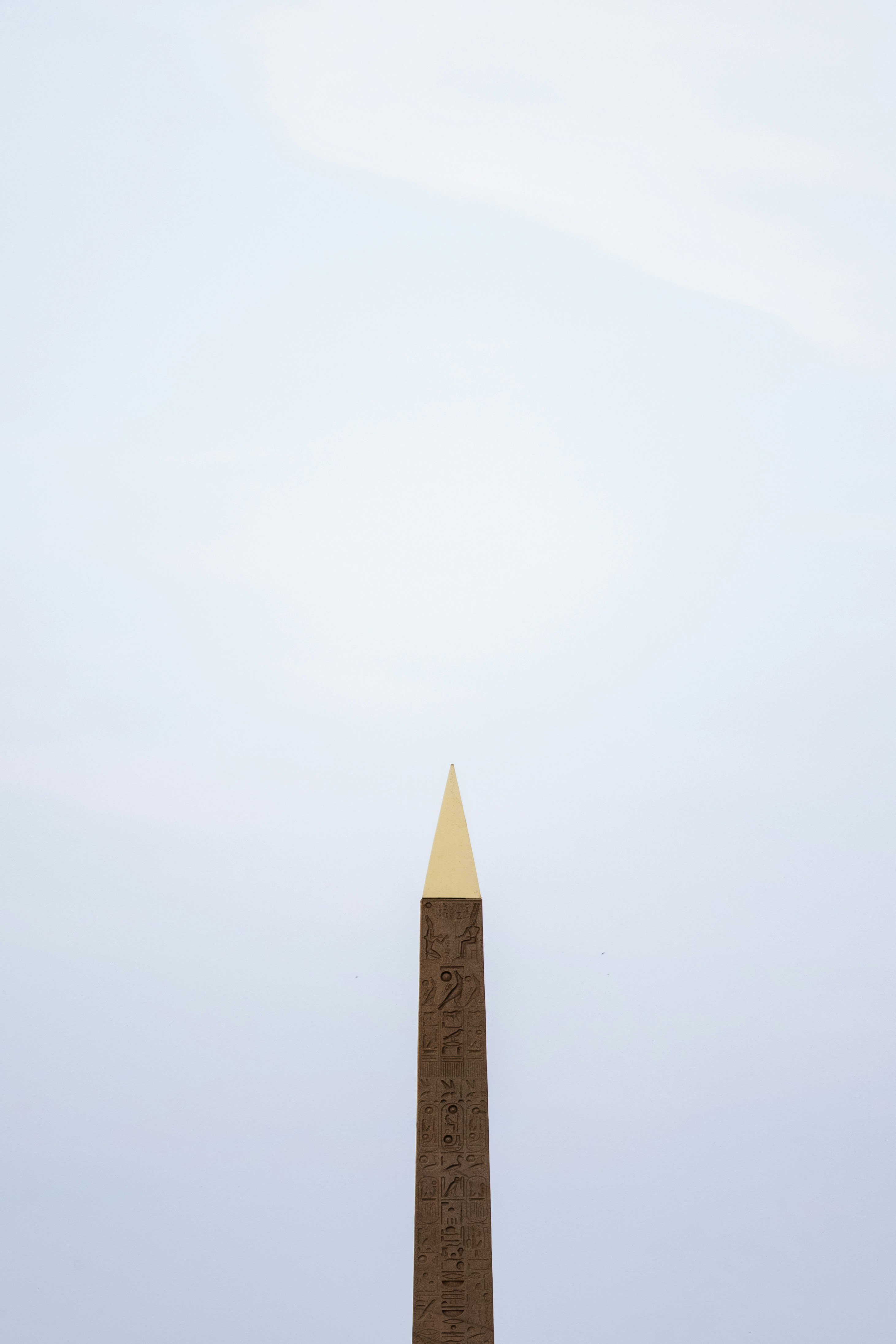 Gold-Tipped Obelisk Against a Quiet Pale Sky