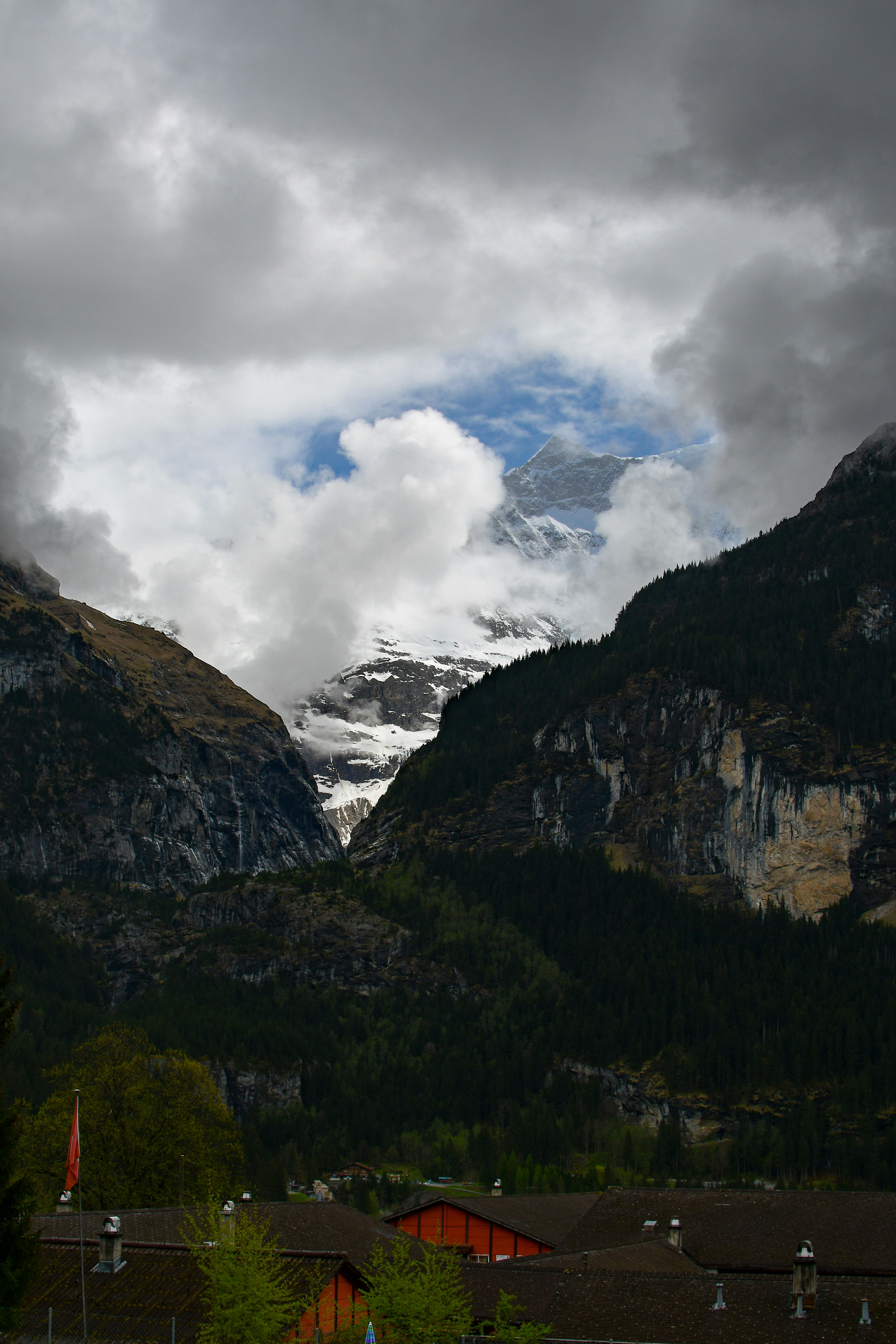 Snowcap Summit Breaking Through Alpine Clouds Over a Quiet Valley Village