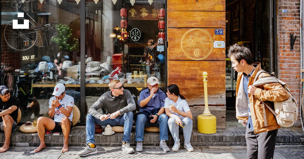 가게 앞 벤치에 앉아 있는 한 무리의 사람들 사진 Unsplash의 무료 바지 이미지