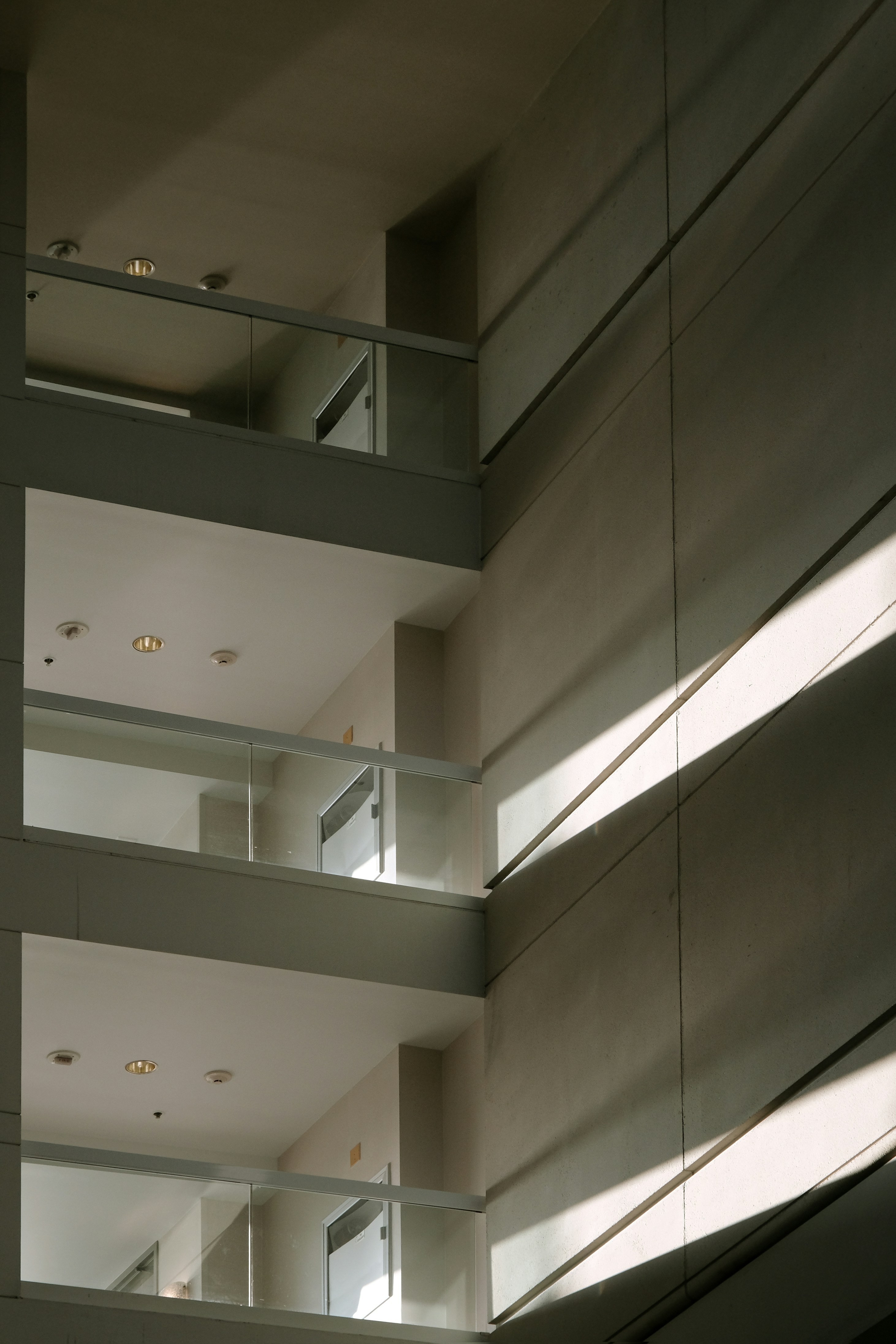 Sunlight casting angular shadows on a multi-level building interior, highlighting clean architectural lines.