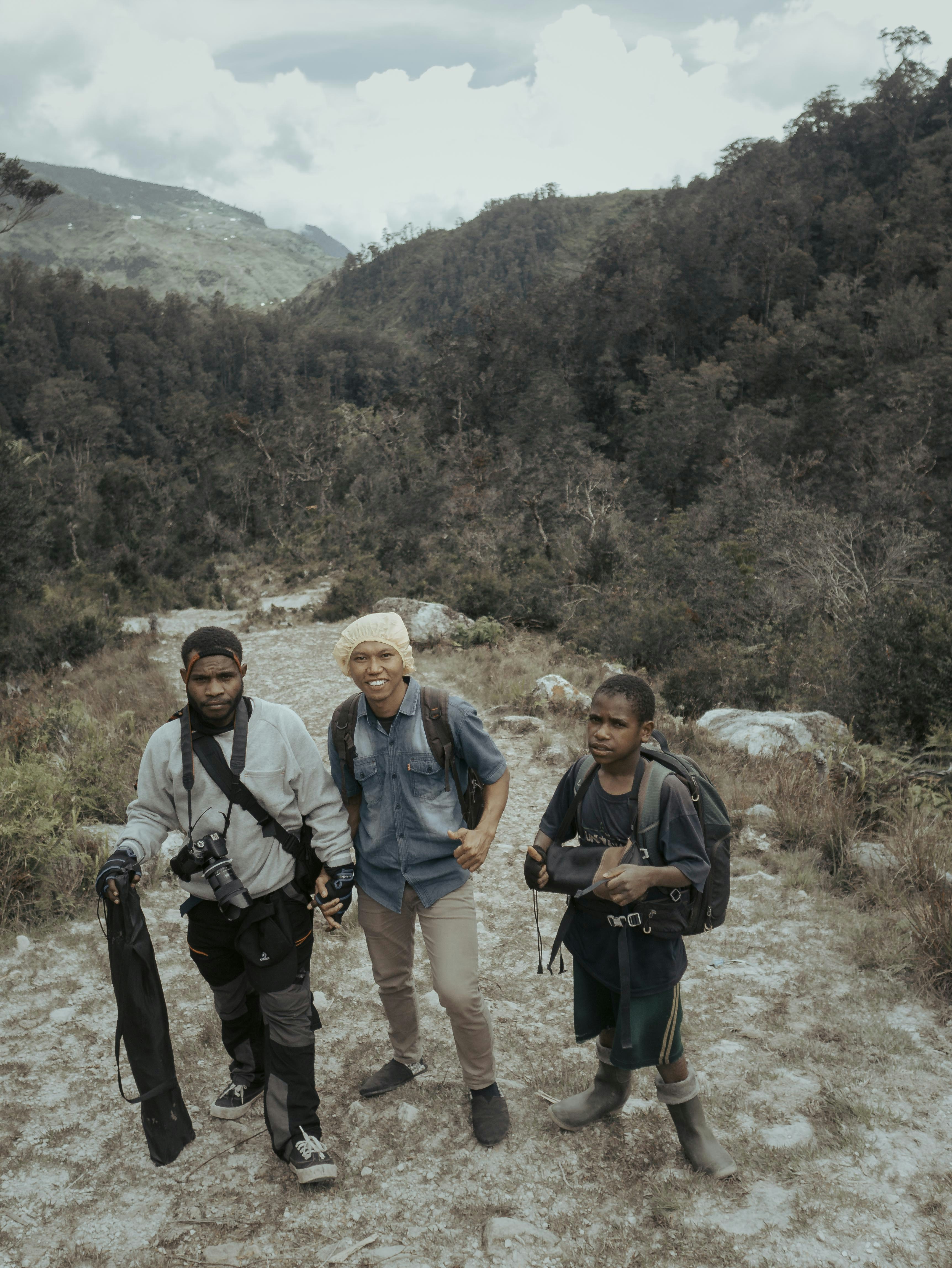 Three Explorers Pause with Gear on a Rocky Ridge Under a Cloudy Sky