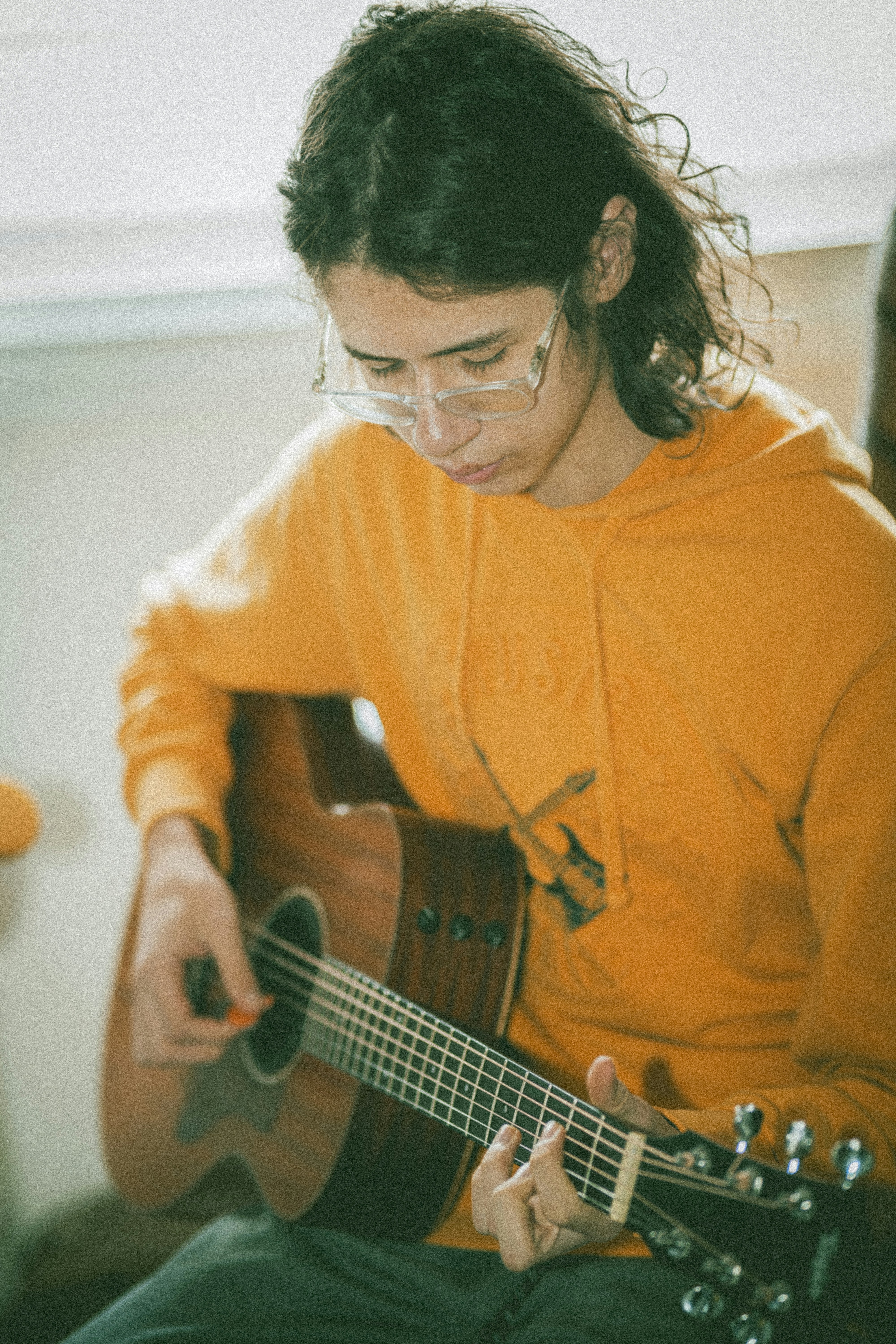Amber Hoodie Guitarist in a Quiet, Grainy Studio Moment