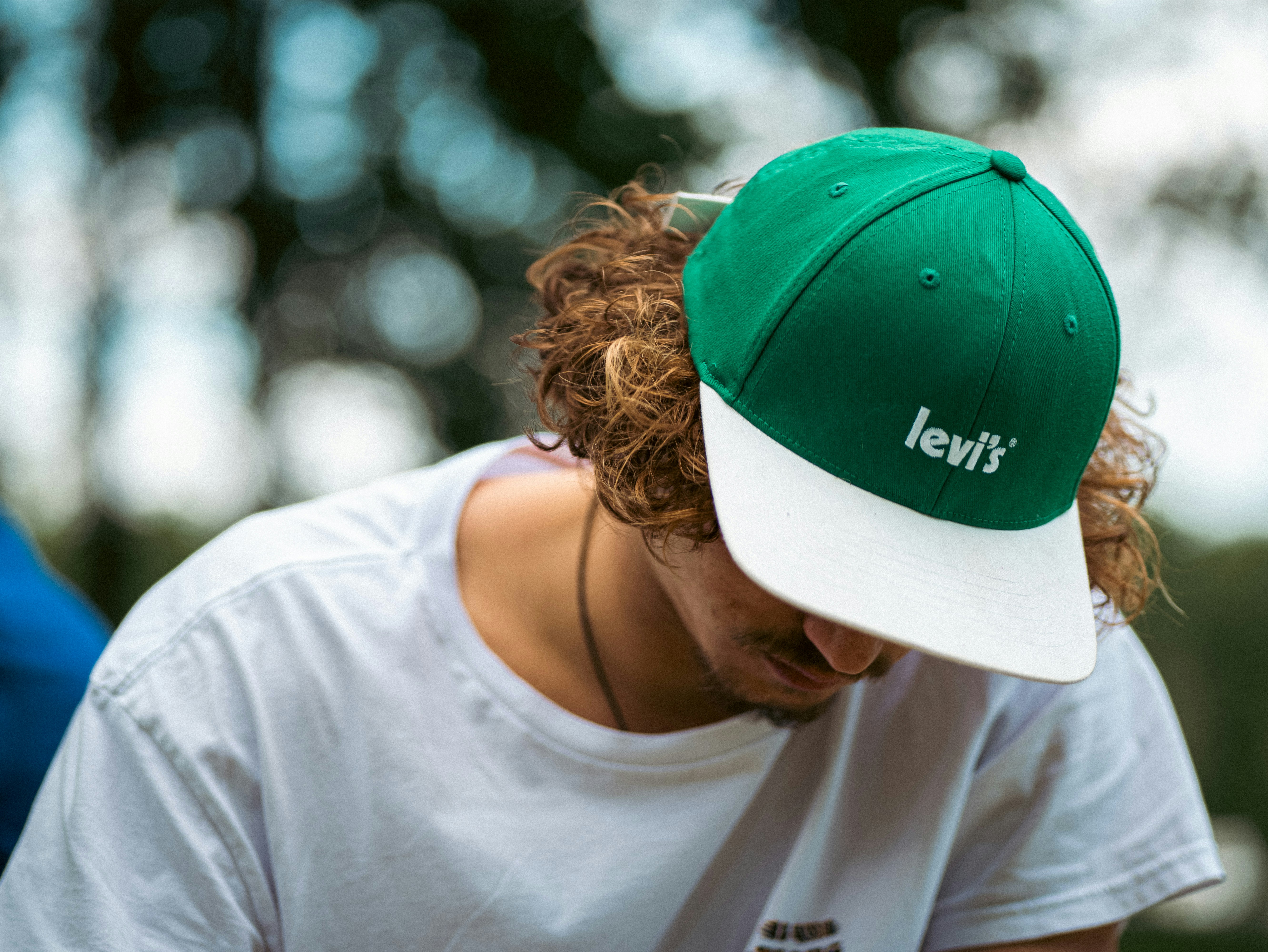Green Cap Focus: A Candid Head-Down Moment in Outdoor Light