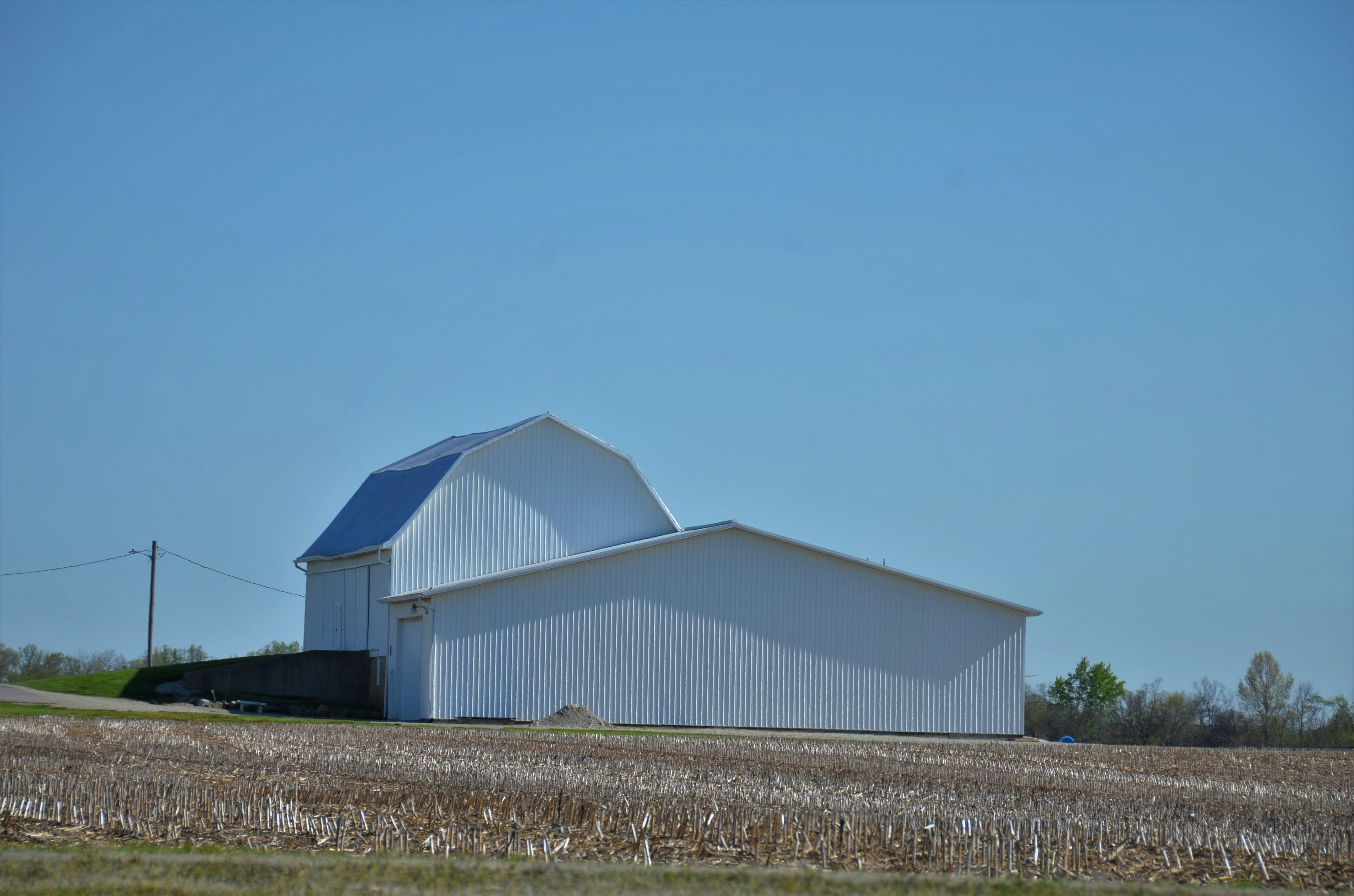 A large white barn sitting on top of a lush green field photo – Free ...