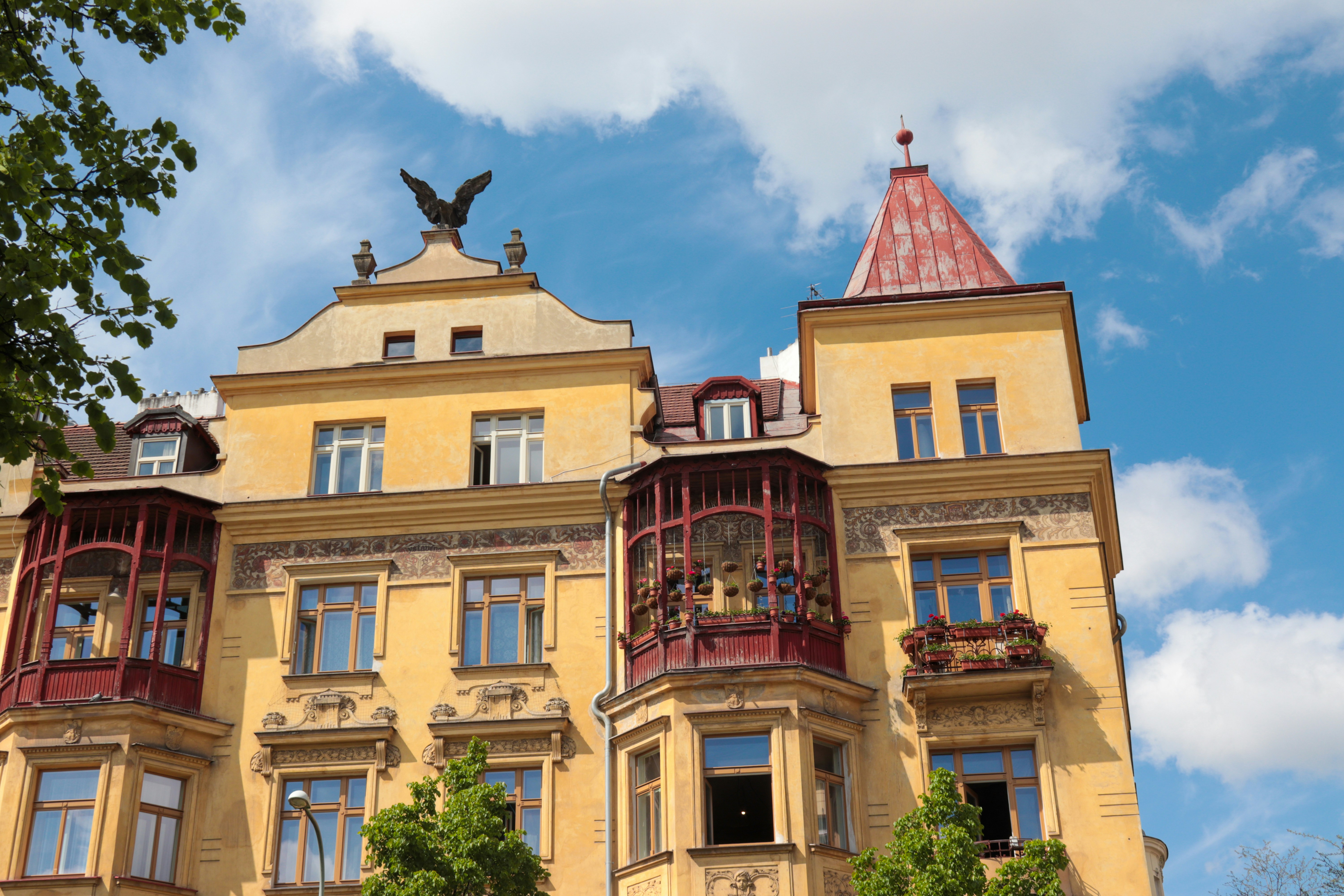 Eagle Crest Over Belle Époque Yellow: A Sunlit Facade with Crimson Verandas