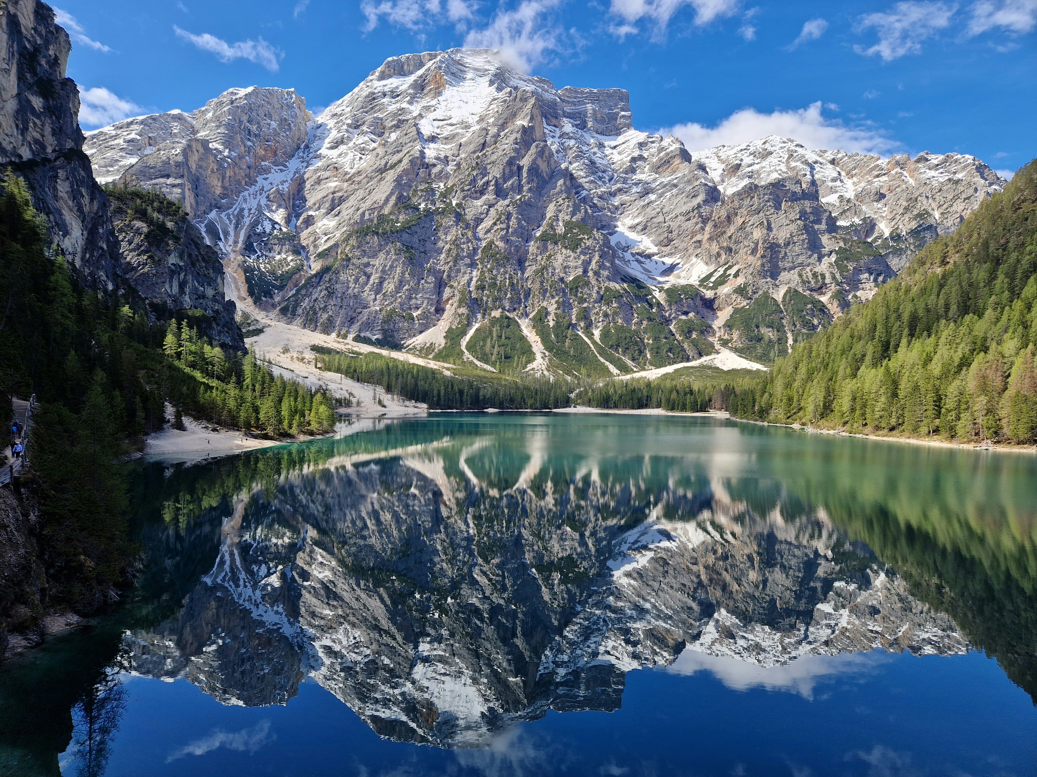 Snow-capped mountains reflected in a tranquil lake under a clear blue sky.