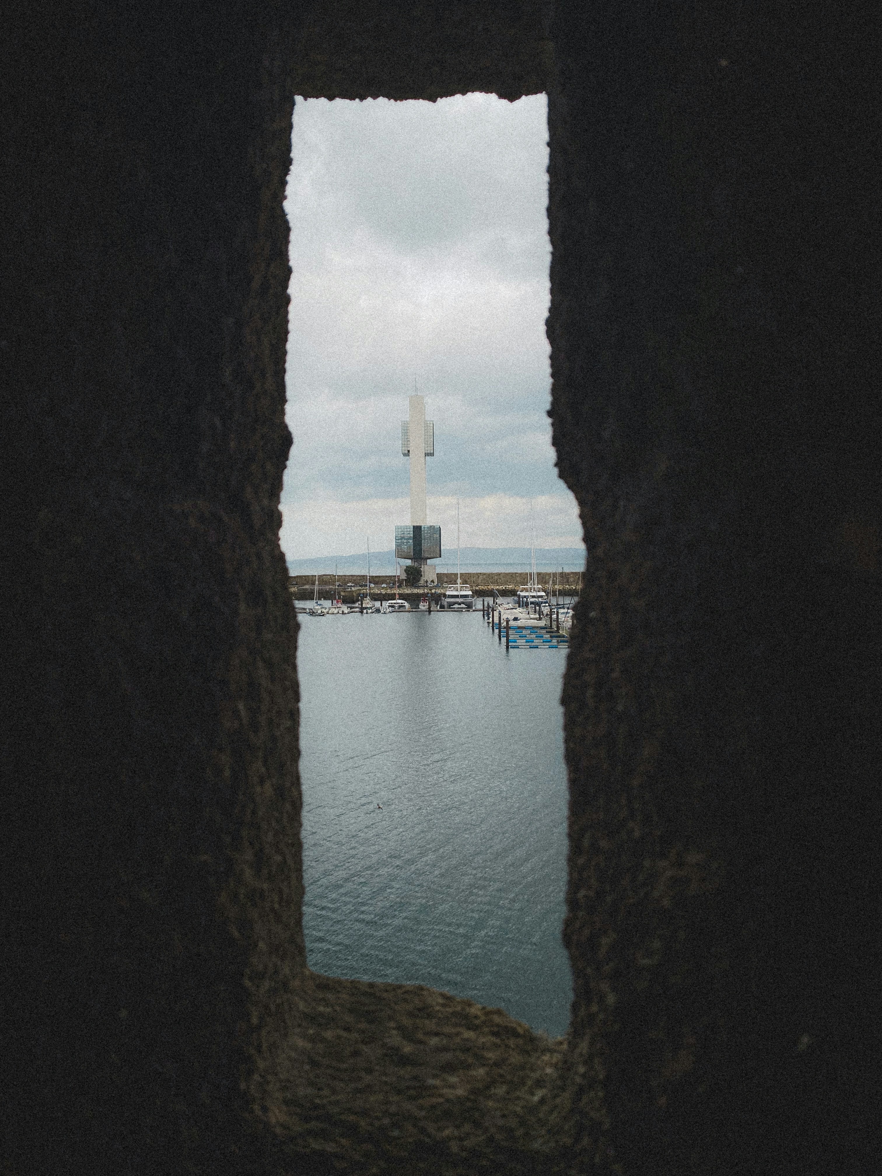 Through the Stone Window: A Harbor Monument Framed by Carved Darkness