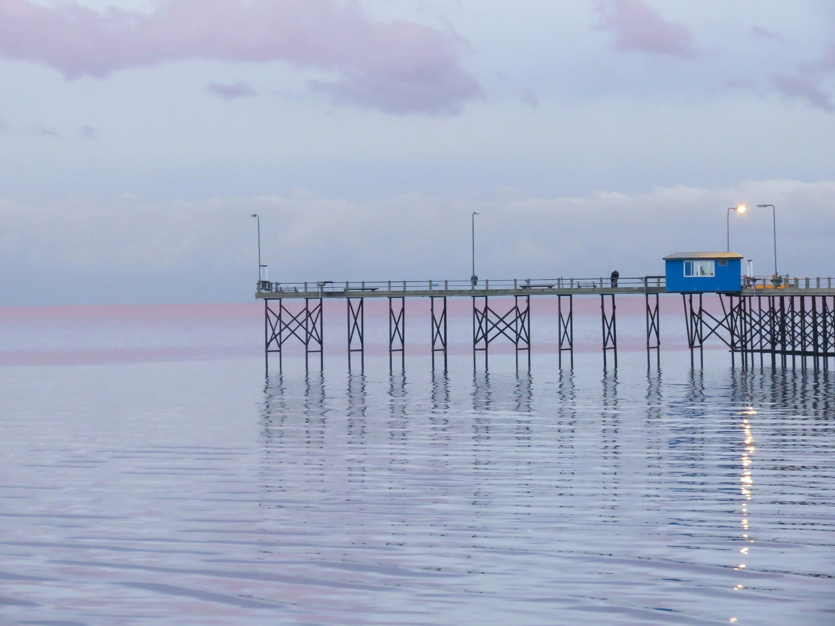 Wooden pier stretching into the calm waters of Río de la Plata under a softly lit evening sky.