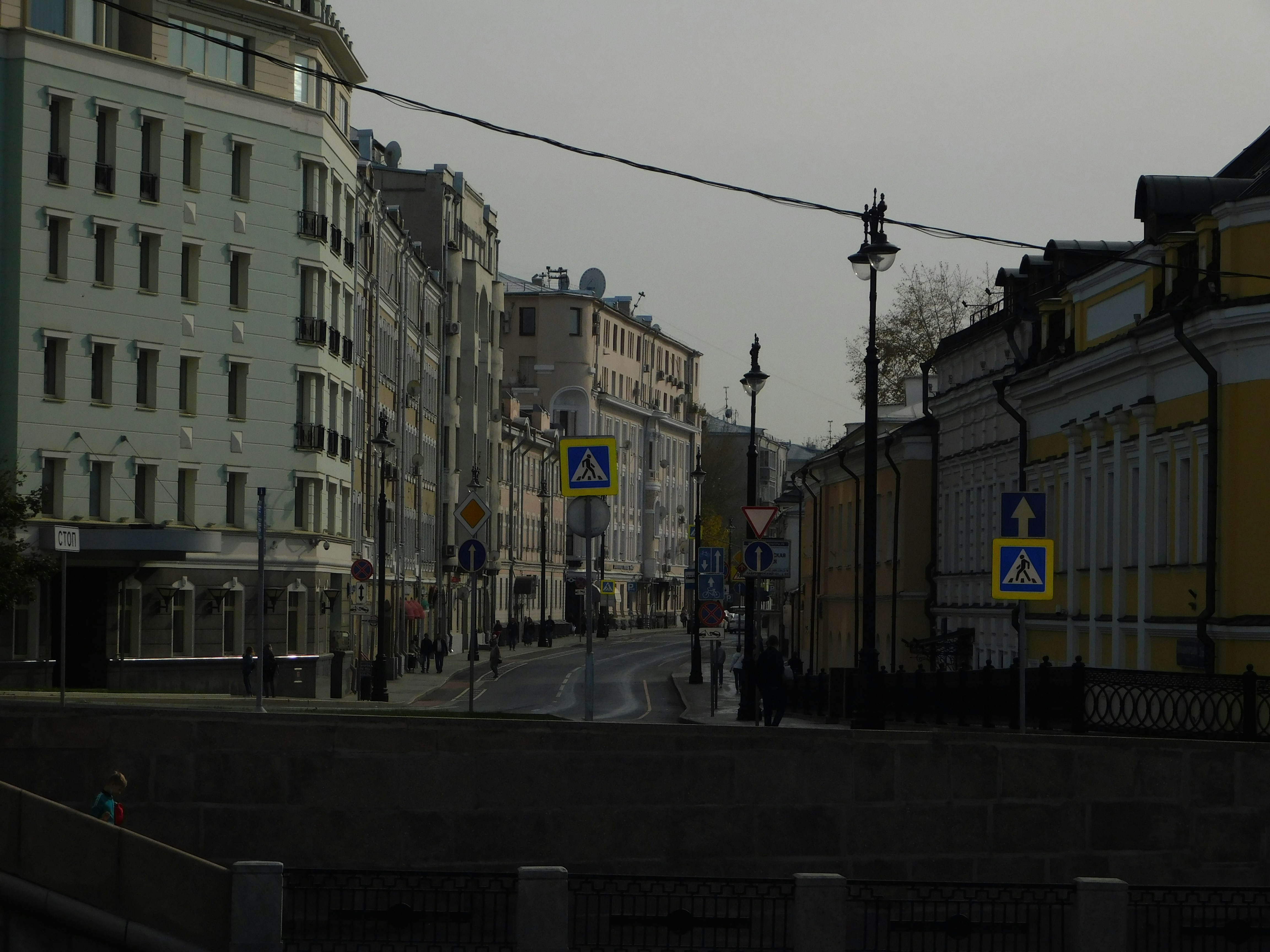 Evening Crosslight: A Quiet Canal Street Framed by Signposts and Timeworn Facades