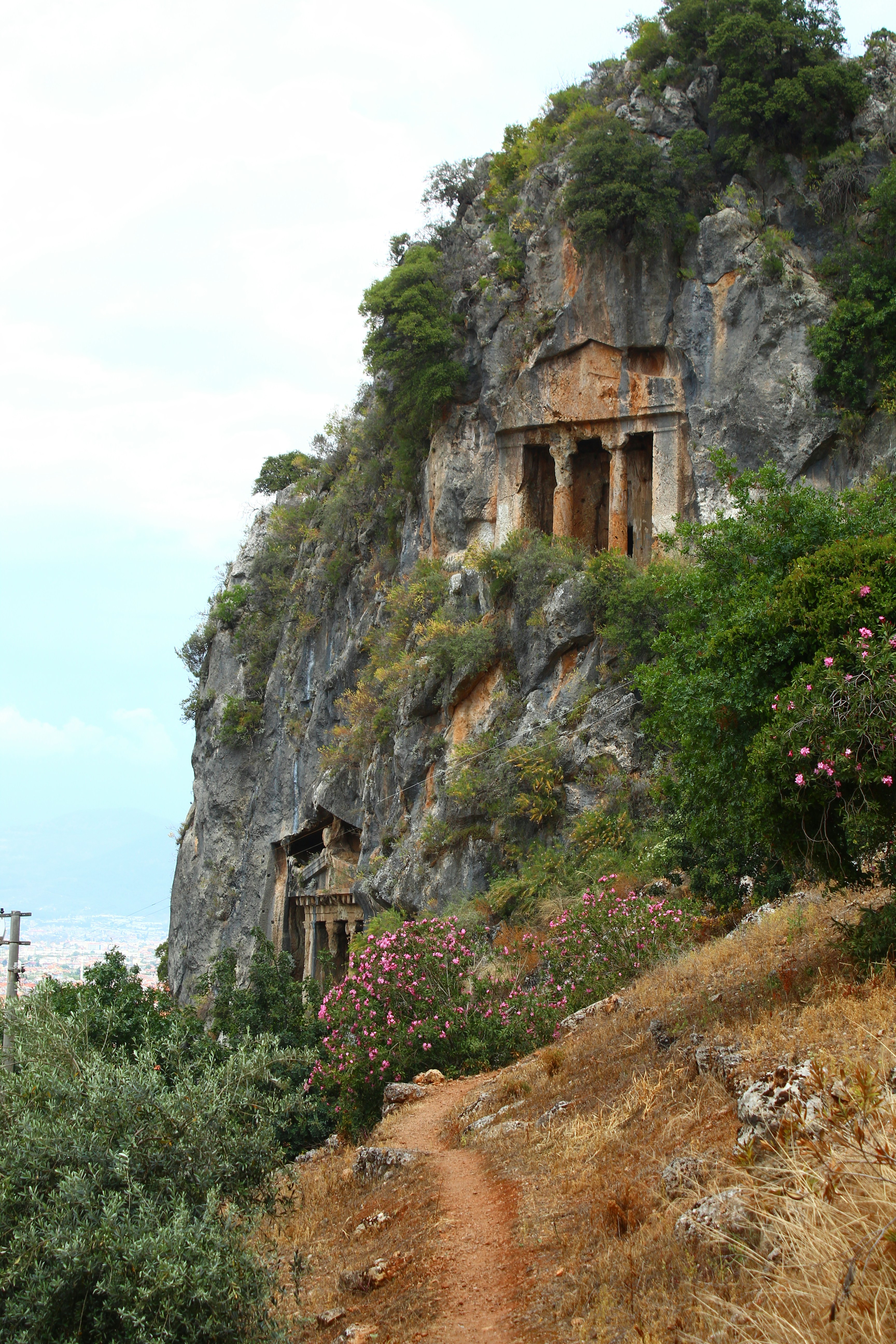 Carved Cliffside Facades Guard a Winding Path on a Limestone Face
