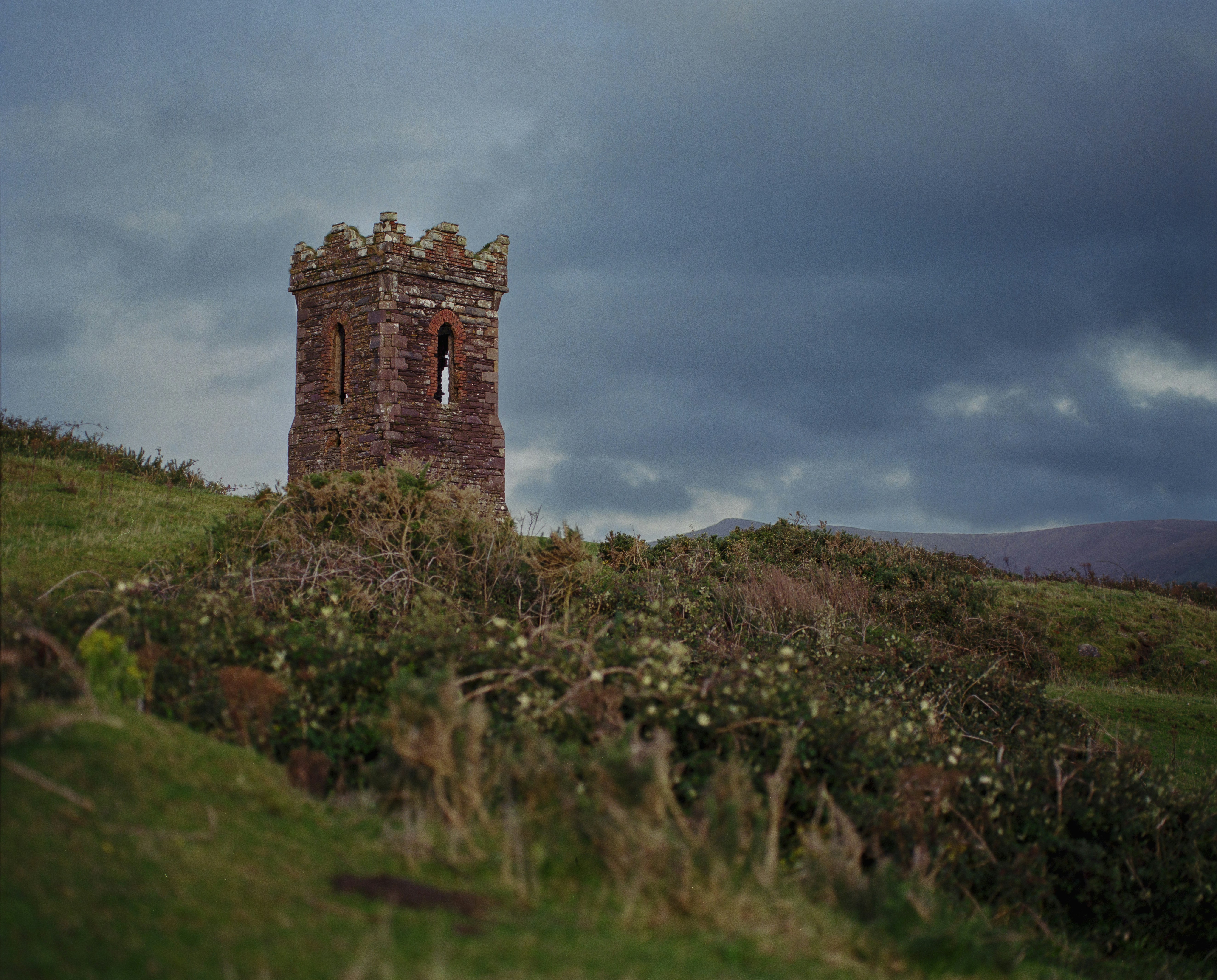 A stone tower sitting on top of a lush green hillside photo – Free ...
